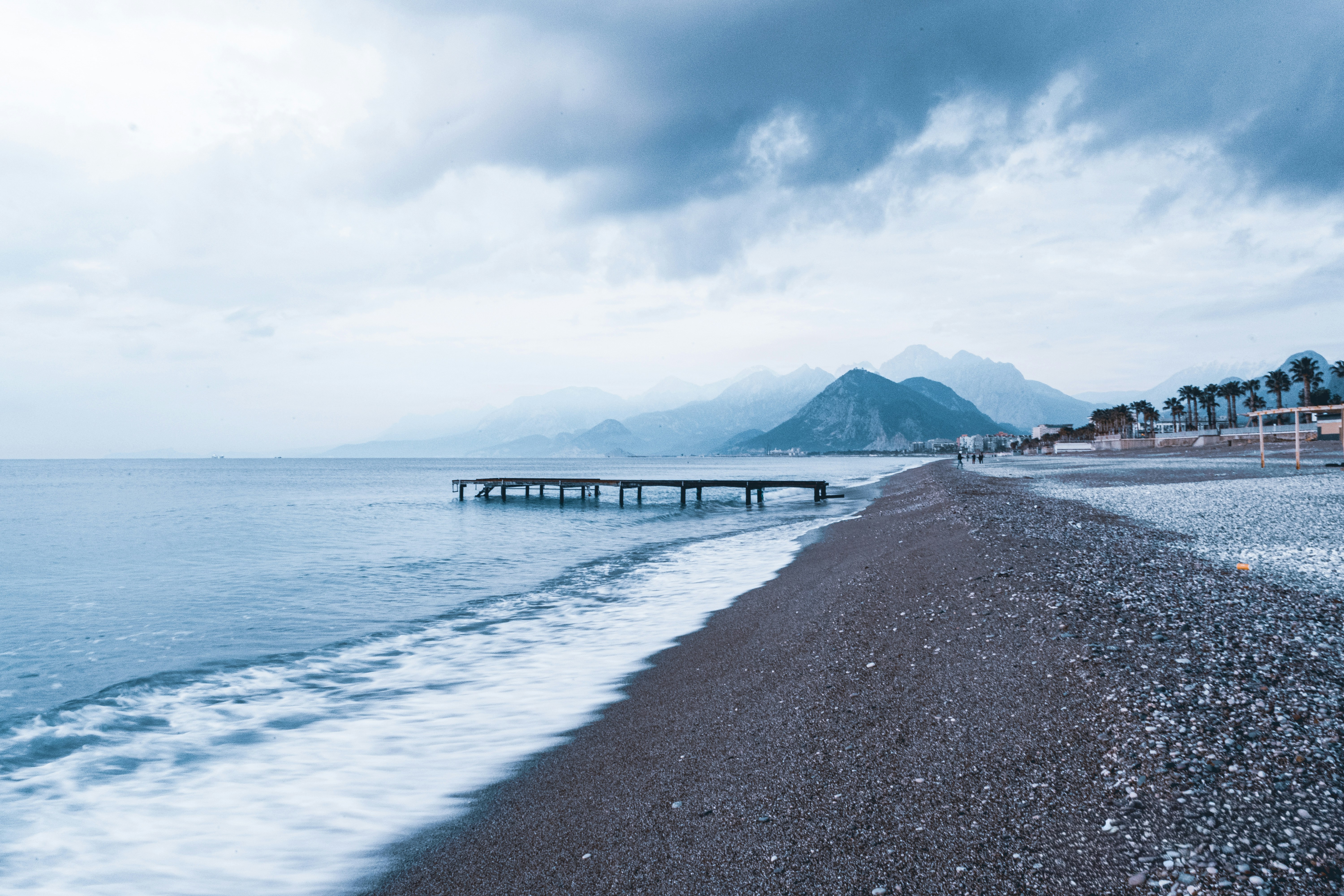 Coastal Tranquility: A Pebble Beach Toward the Distant Mountains