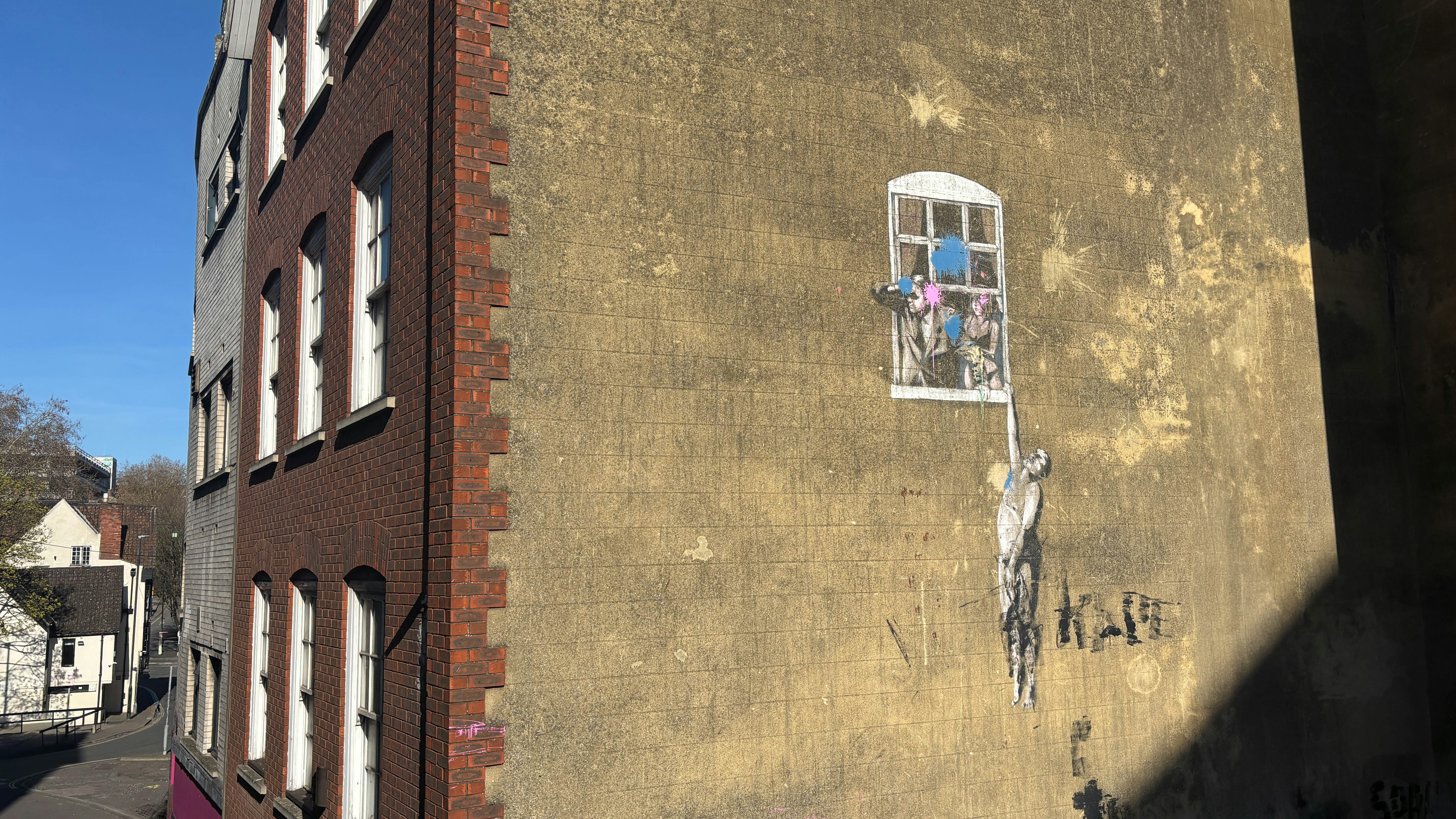 Adolescent mural on sunlit brick wall with alleyway perspective