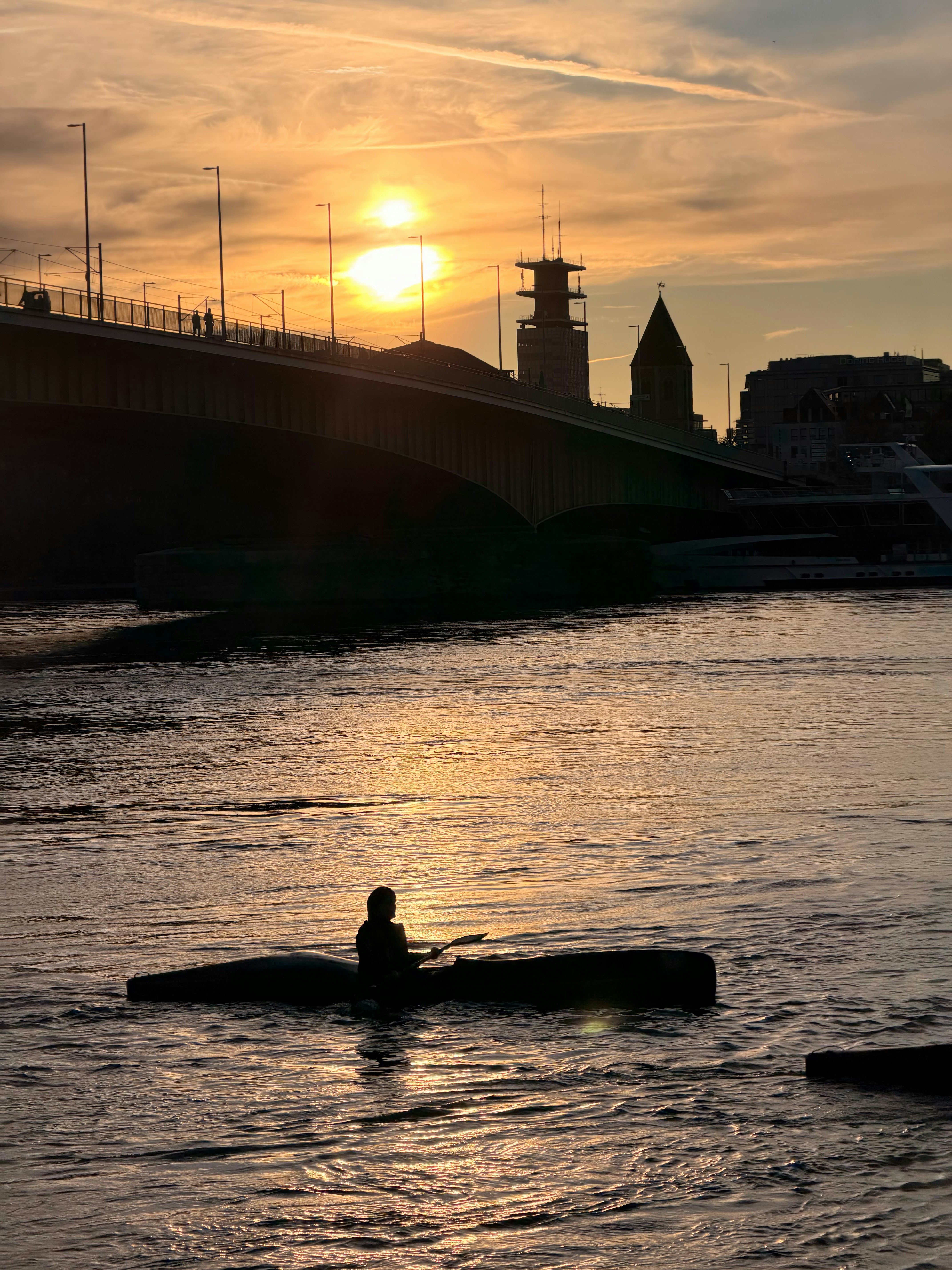 Dusk on the River: silhouette paddler beneath a sunlit skyline