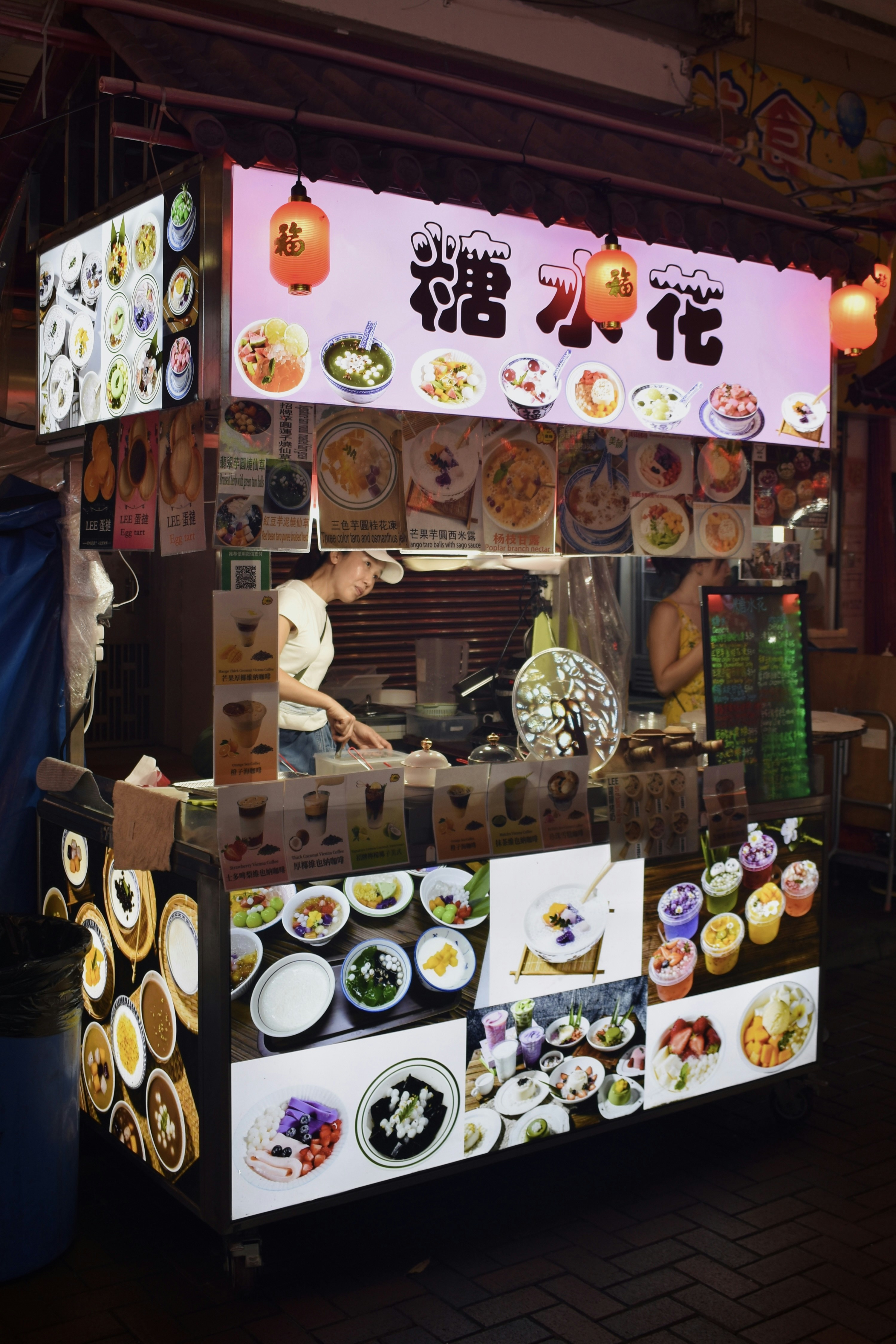 Vibrant street food stall at night with illuminated sign and array of plated dishes on display.