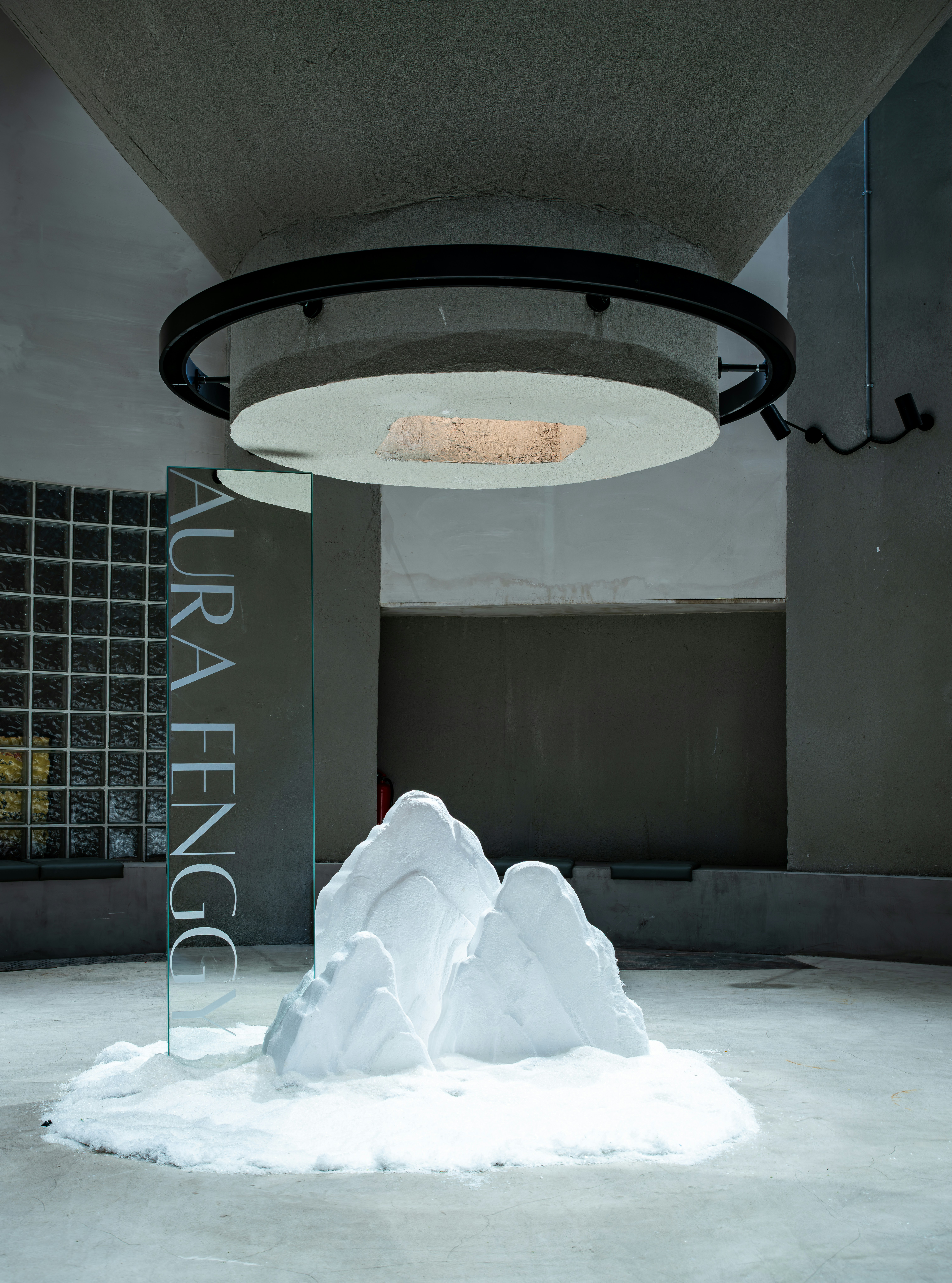 Snowlit sculpture under a circular architectural light at a modern museum entrance