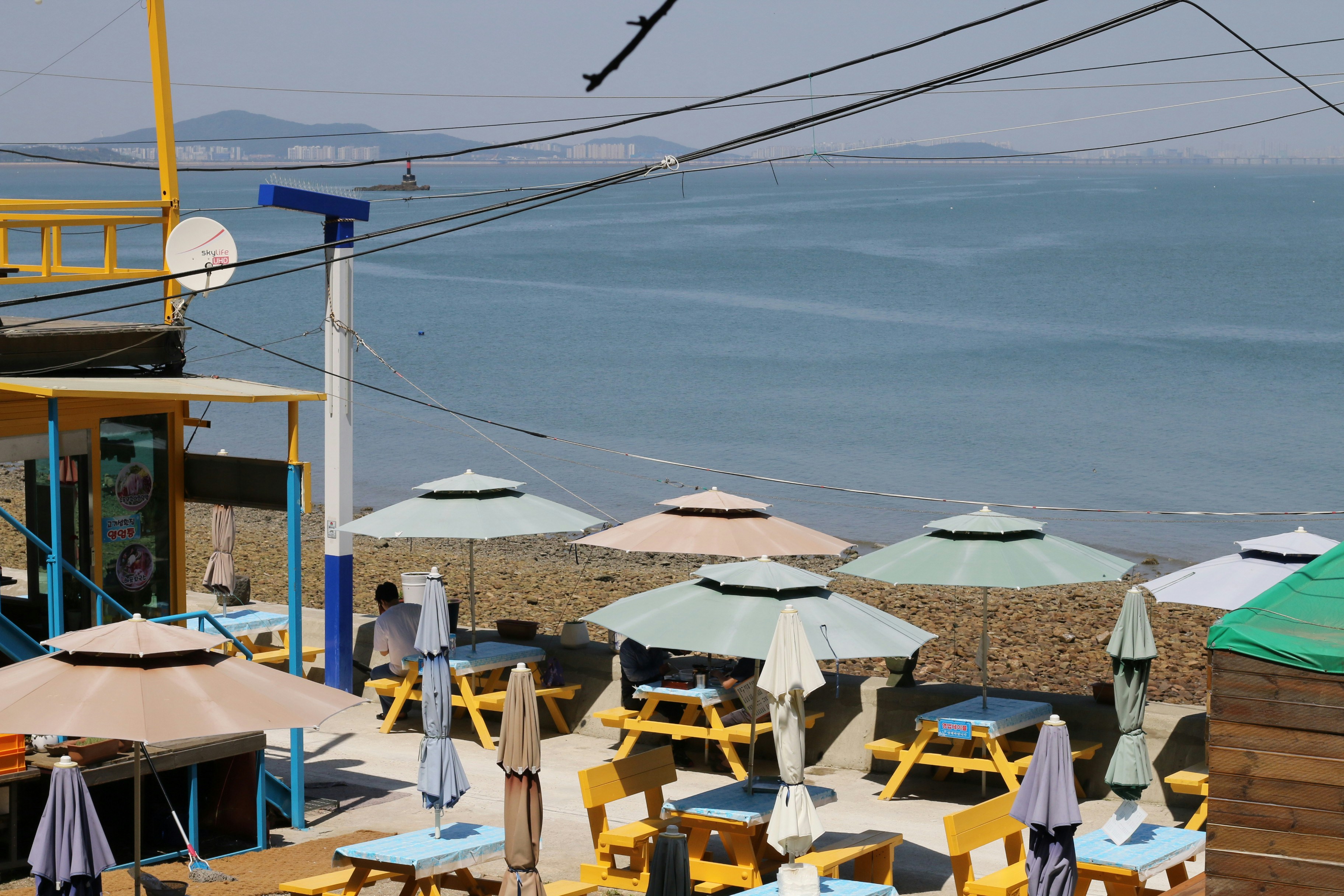 Sunlit seaside café under pastel umbrellas