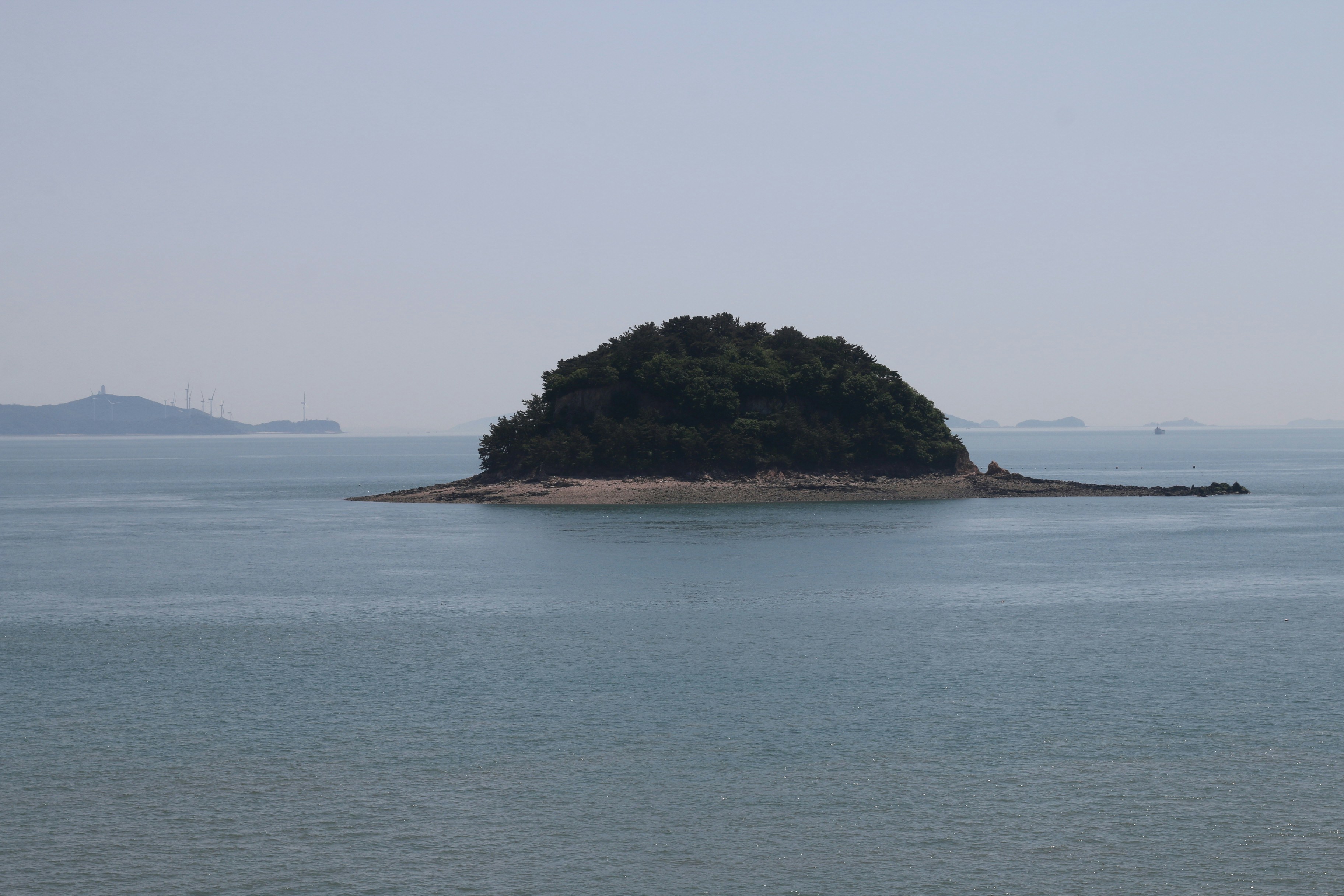 Isolated Island: Calm Sea Embraces a Quiet Green Peak