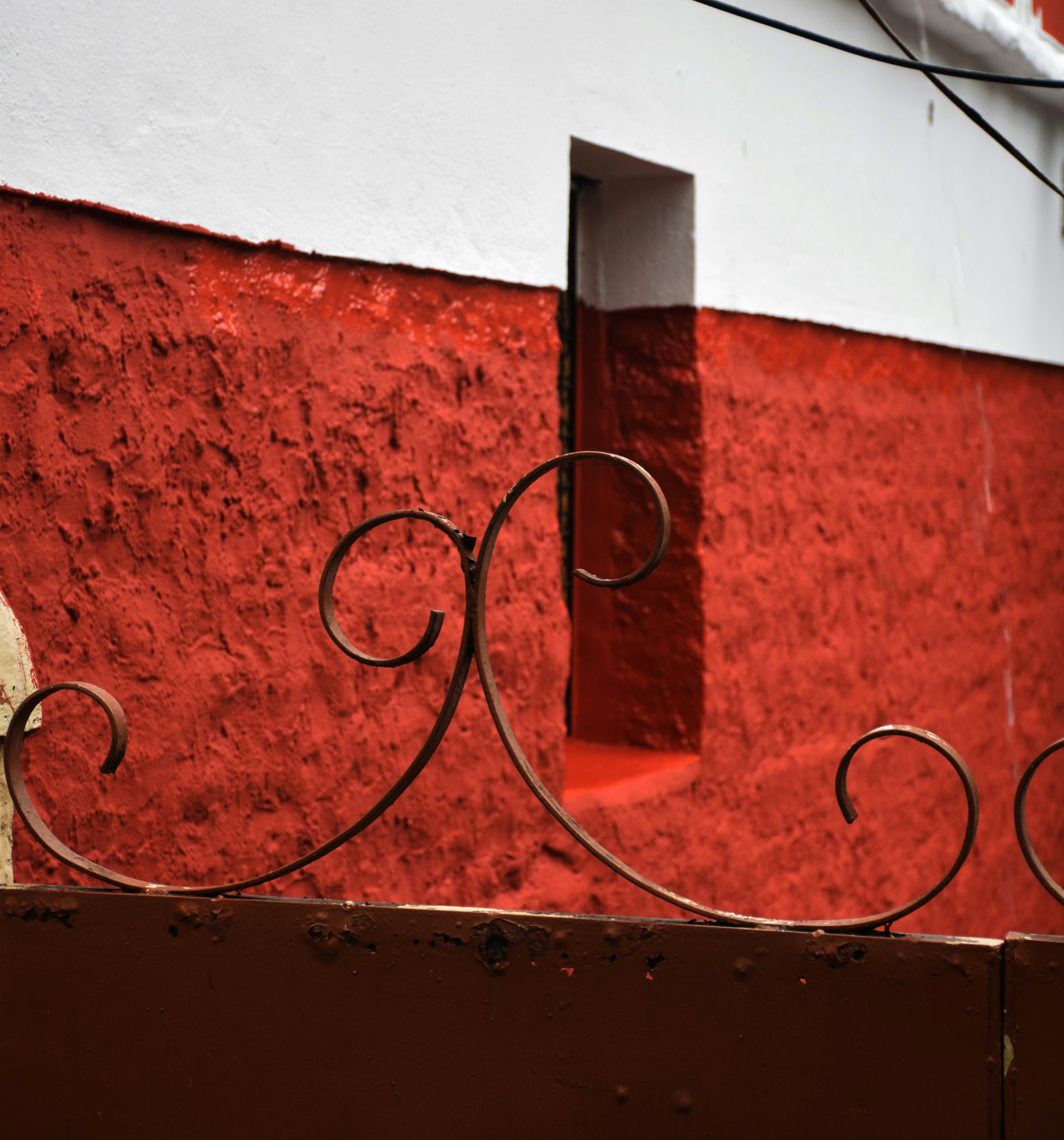 Curved Wrought Iron Threads Against a Crimson Wall