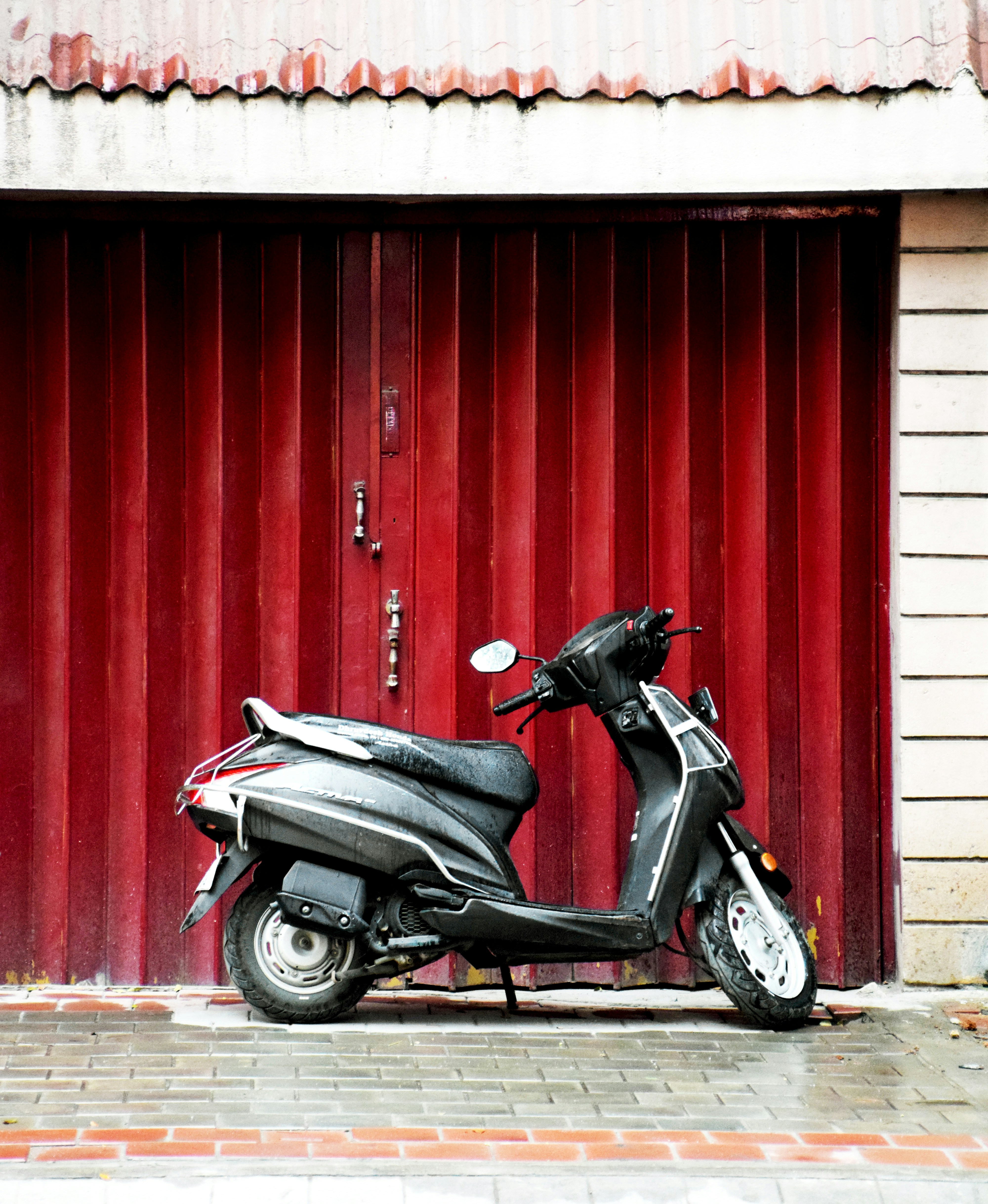 Scooter Resting Against a Crimson Gate