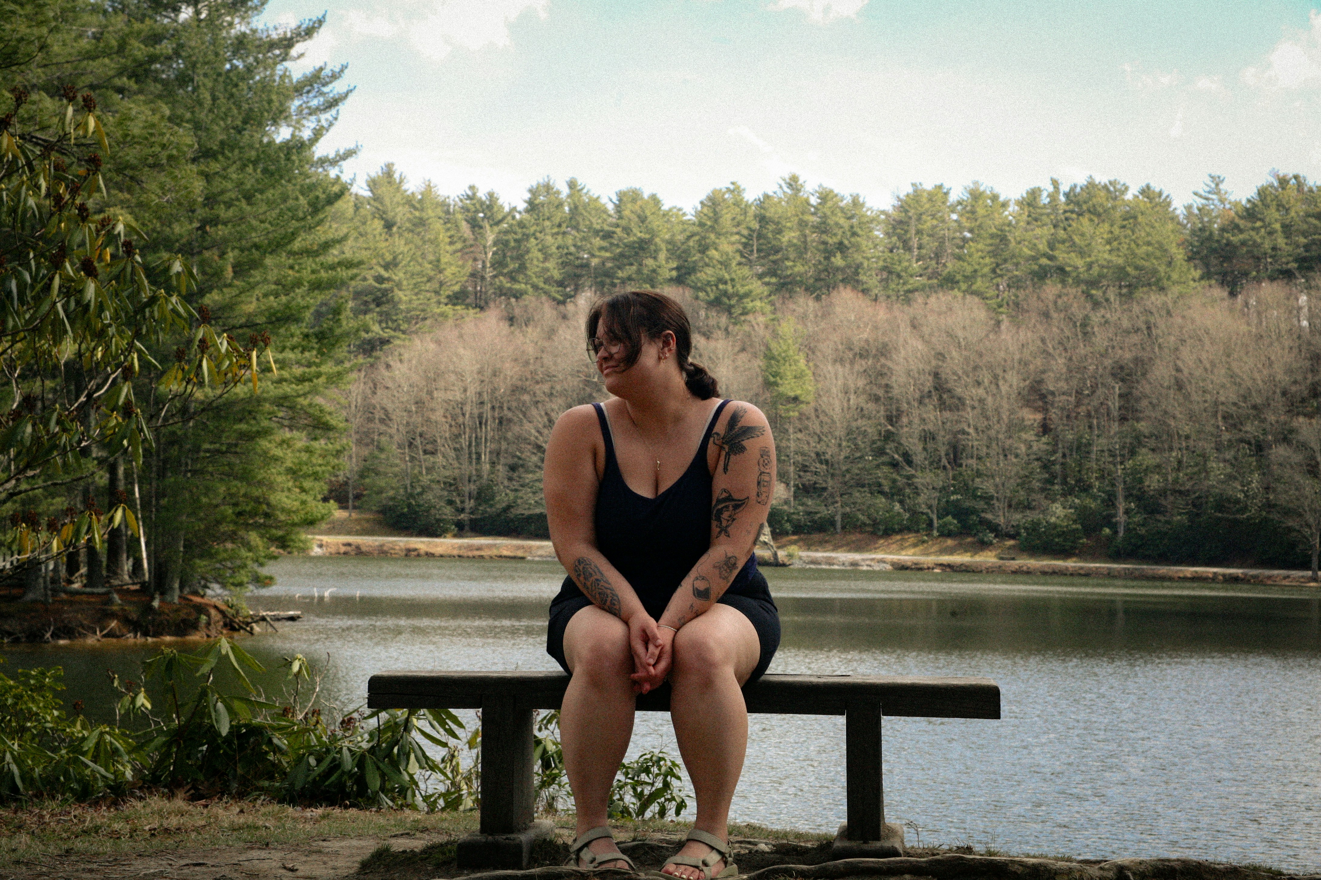 Quiet Riverside Moment: A Woman on a Bench by the Pines