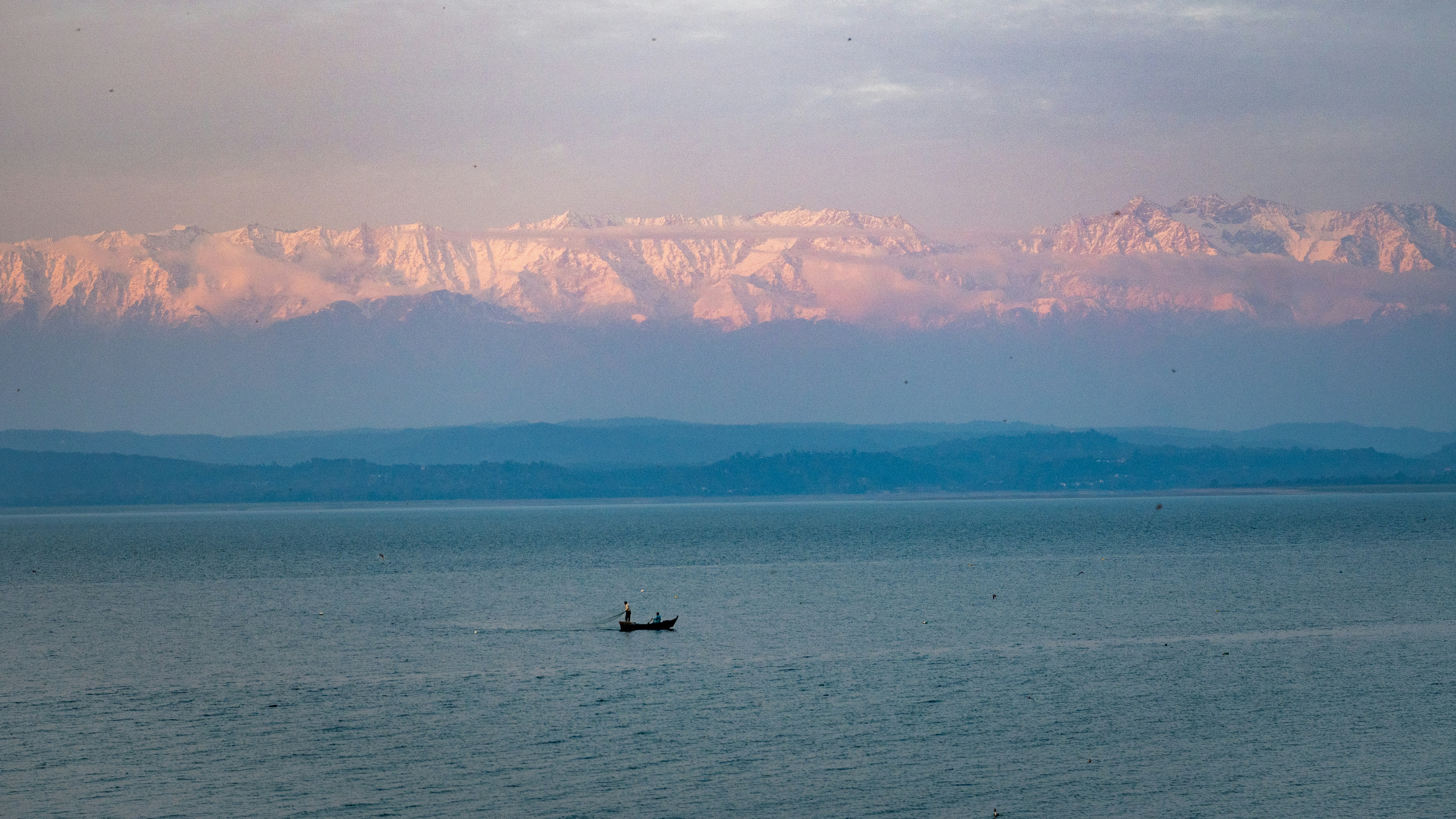 Soft Horizons: A Lone Rowboat Crossing a Quiet Sea