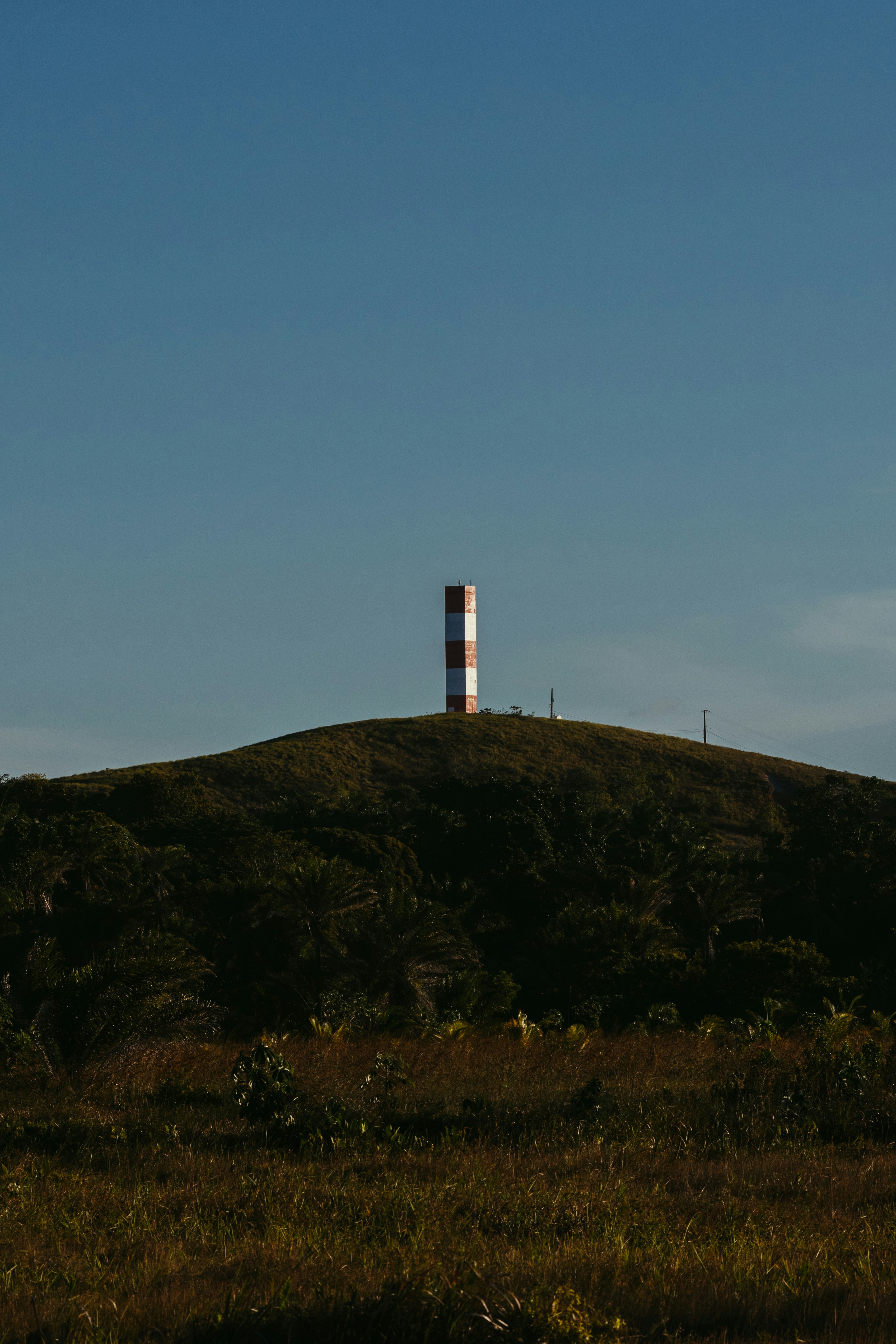Monolith on the Hill: A Striped Tower Silhouette Against a Clear Sky