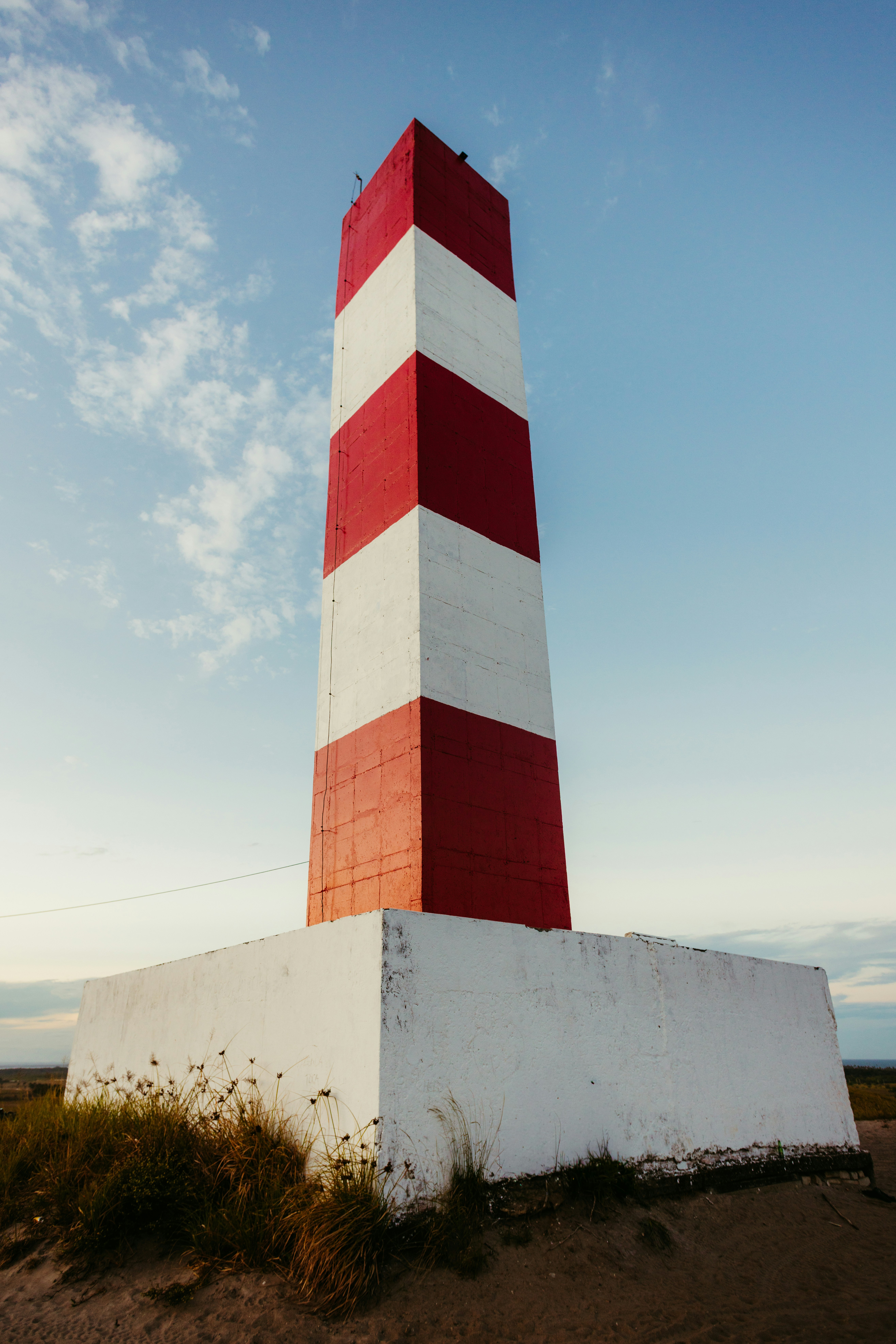 Red-White Striped Beacon Rising from Sands at Dusk