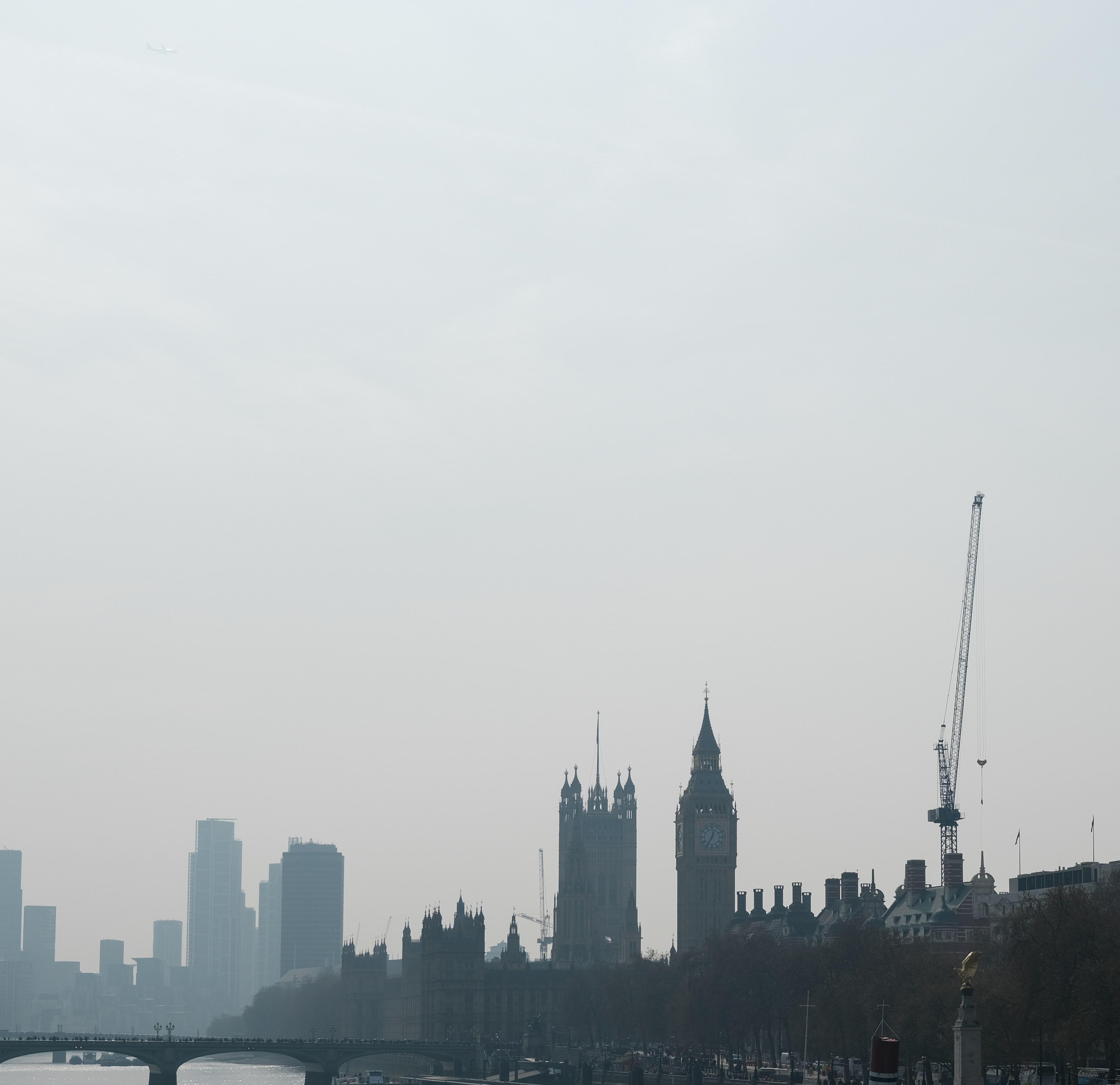 City Silhouette at Dusk: Towers and Crane Amid Riverside Fog