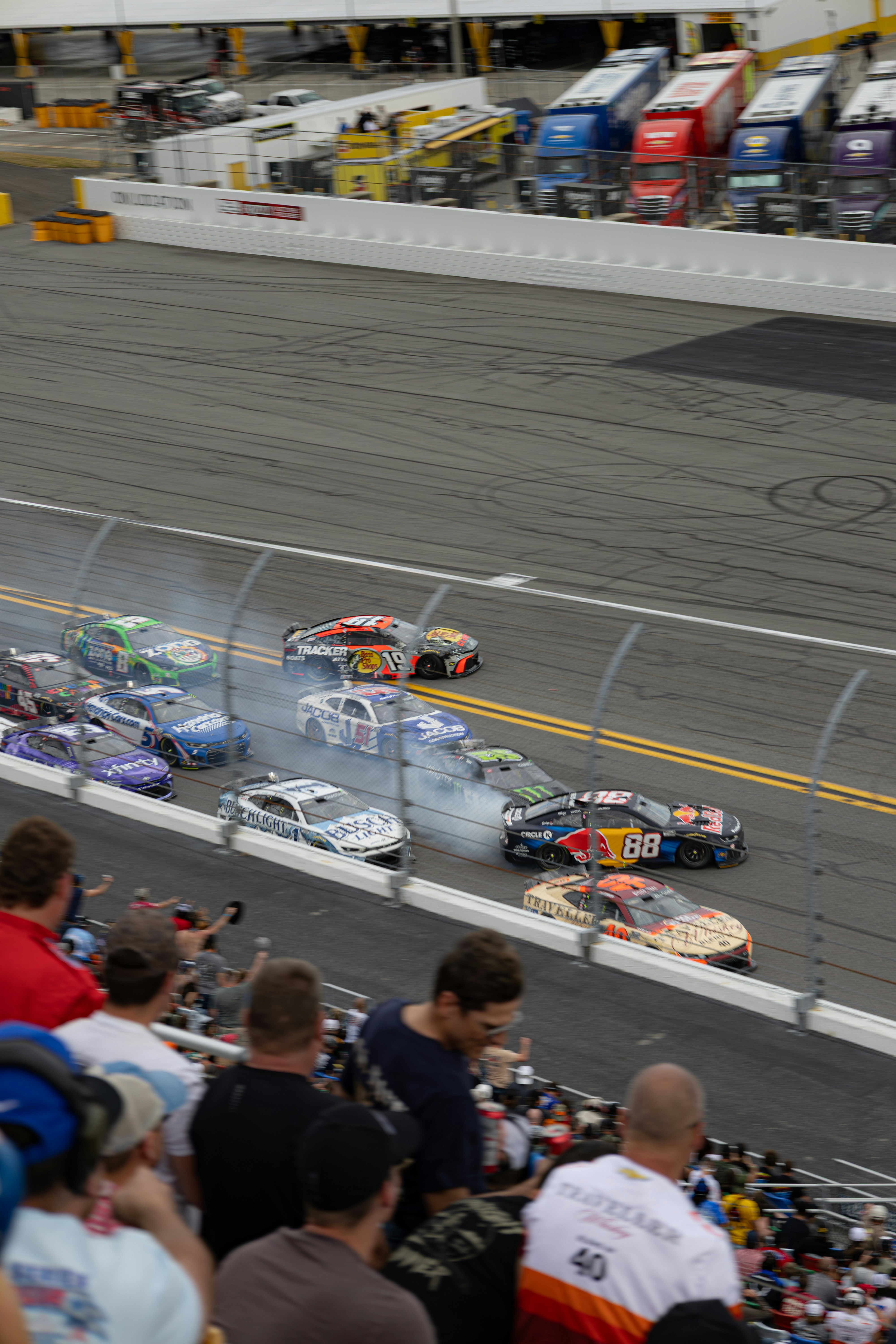 Finish Line Frenzy: Race Cars Power Through Turn Amidst Cheering Grandstands