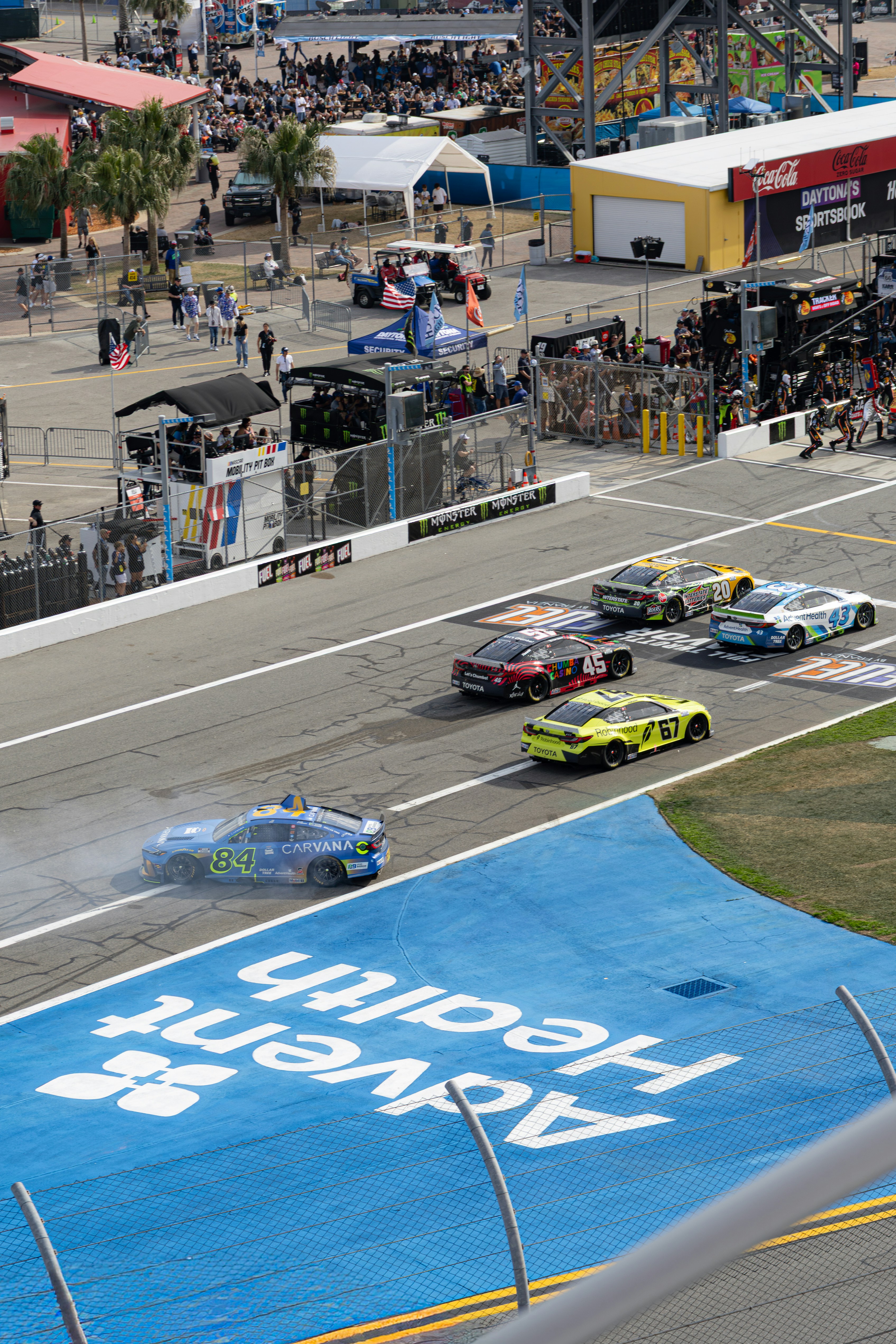 Pace Carfront: Race Cars Flaring Through Pit Lane at Daytime Speedway