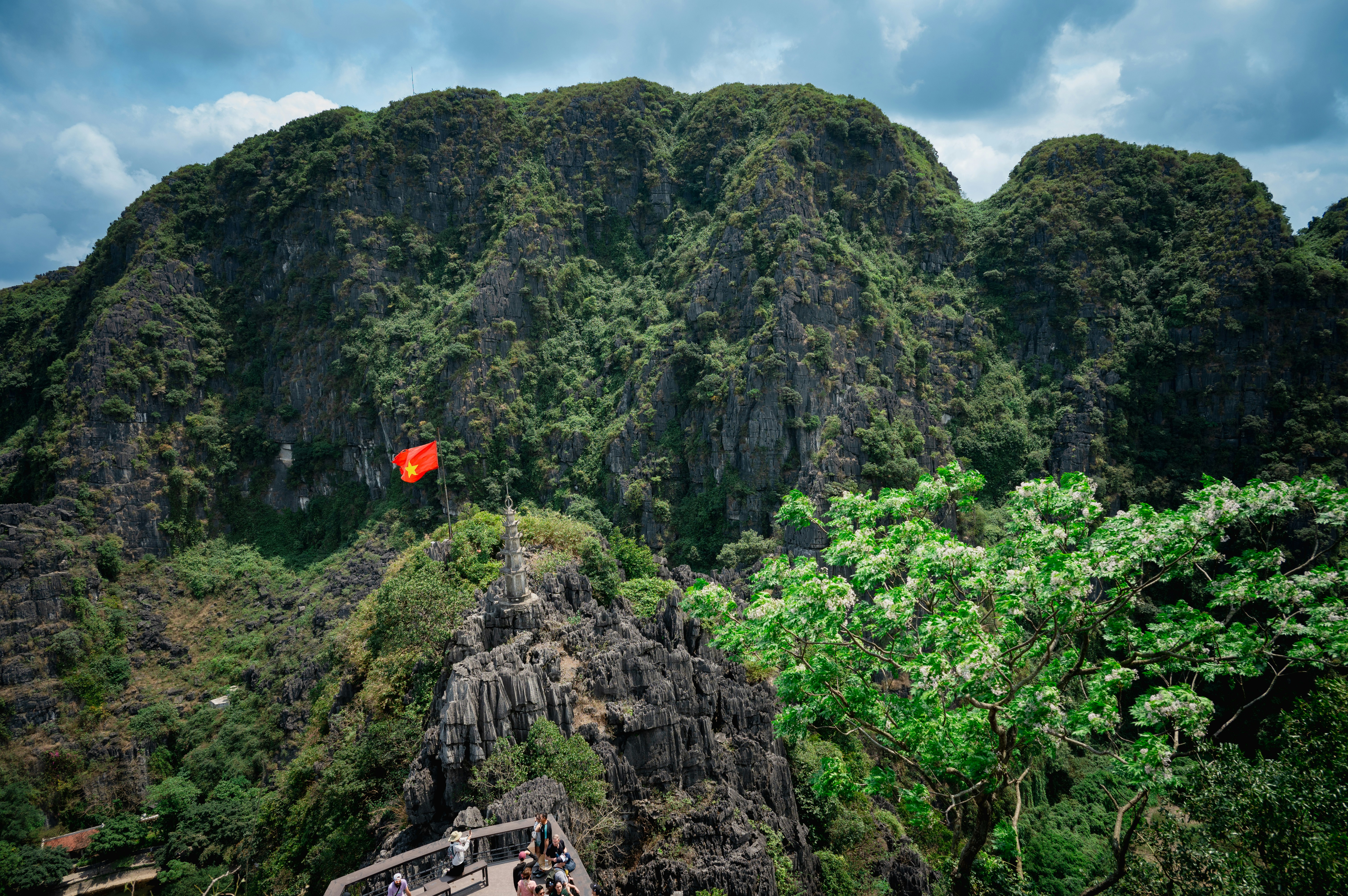 Flag over jagged green cliffs: ritual peak in foggy valley
