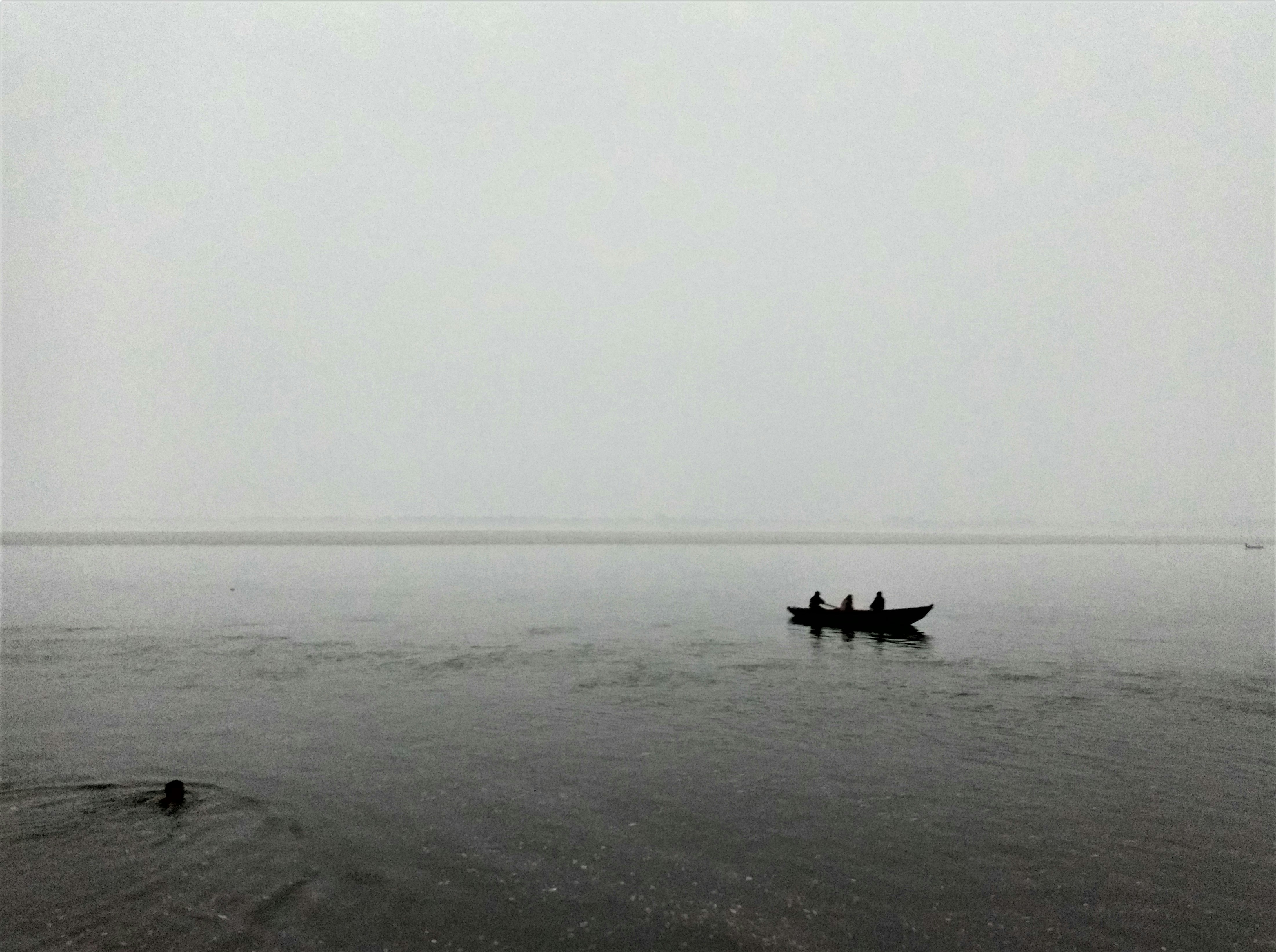 Two-boat silhouette at horizon over quiet, misty water