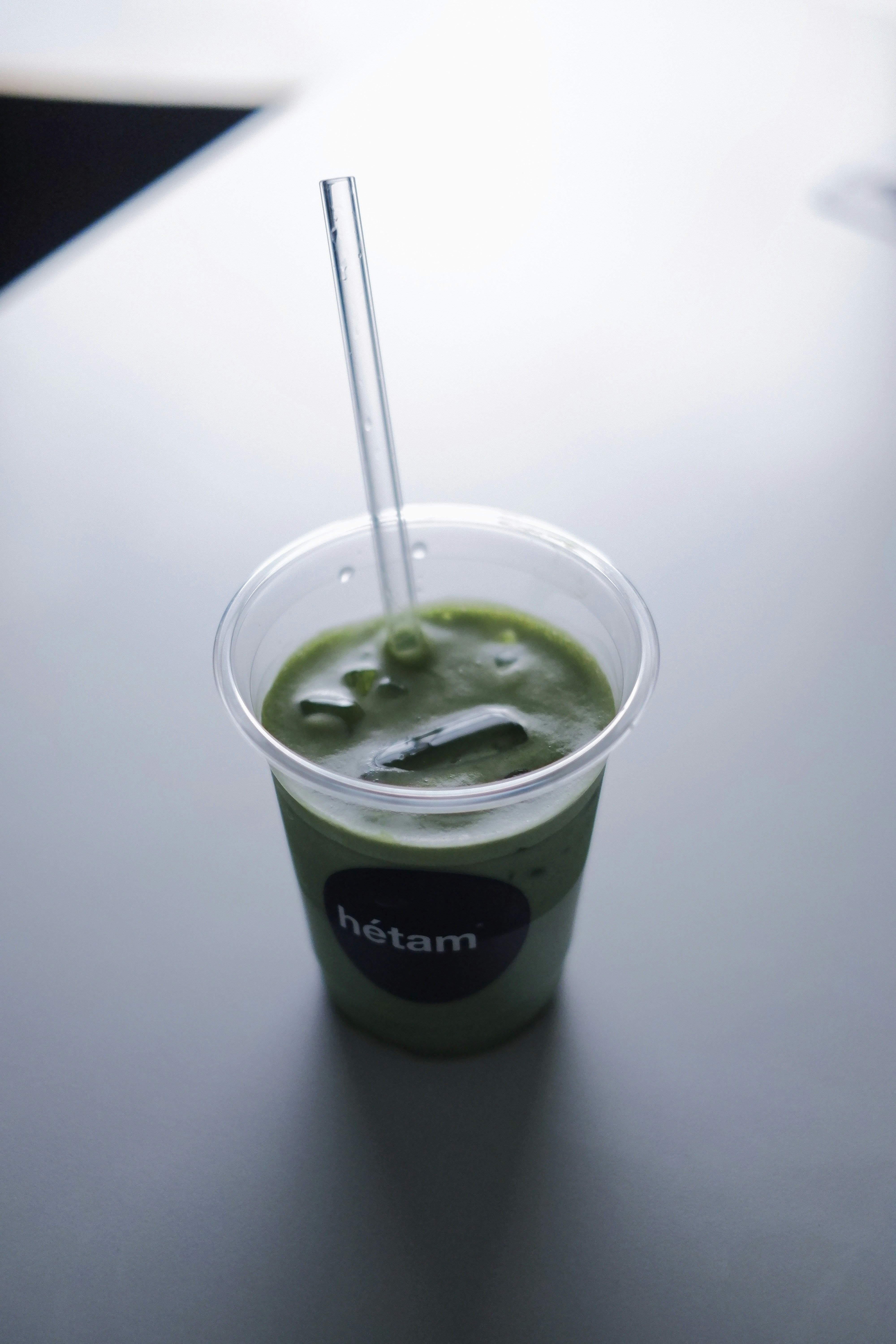 Green Smoothie in Focus: Ice and Straw Framed by Soft Backdrop
