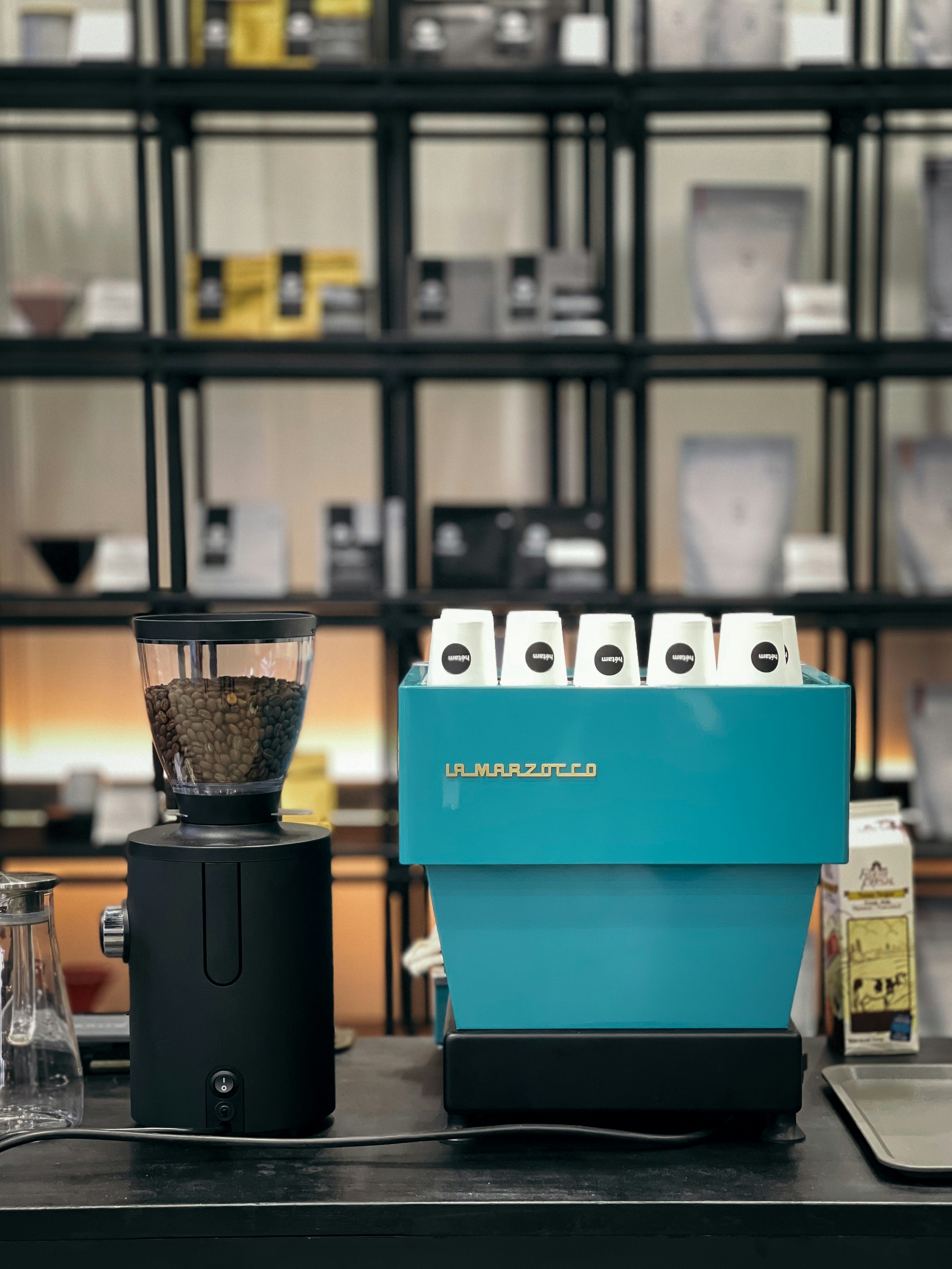 Blue espresso station: a coffee grinder and bright teal espresso machine in a modern cafe