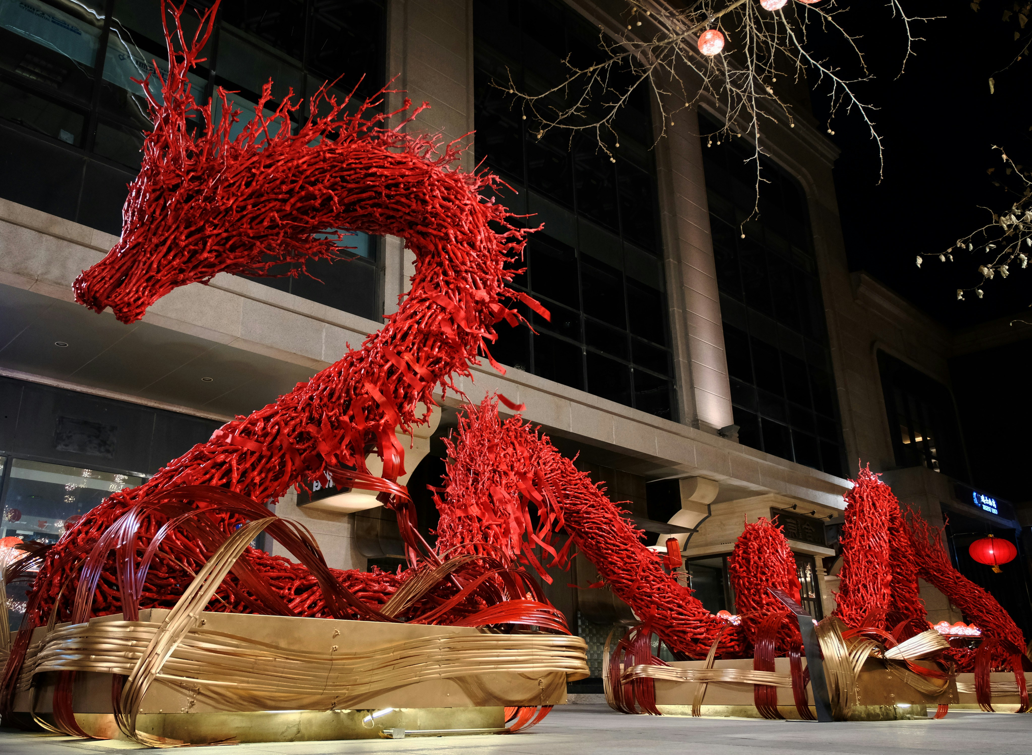 Scarlet Serpents: A Display of Dynamic Red Sculptures on Golden Ribbons