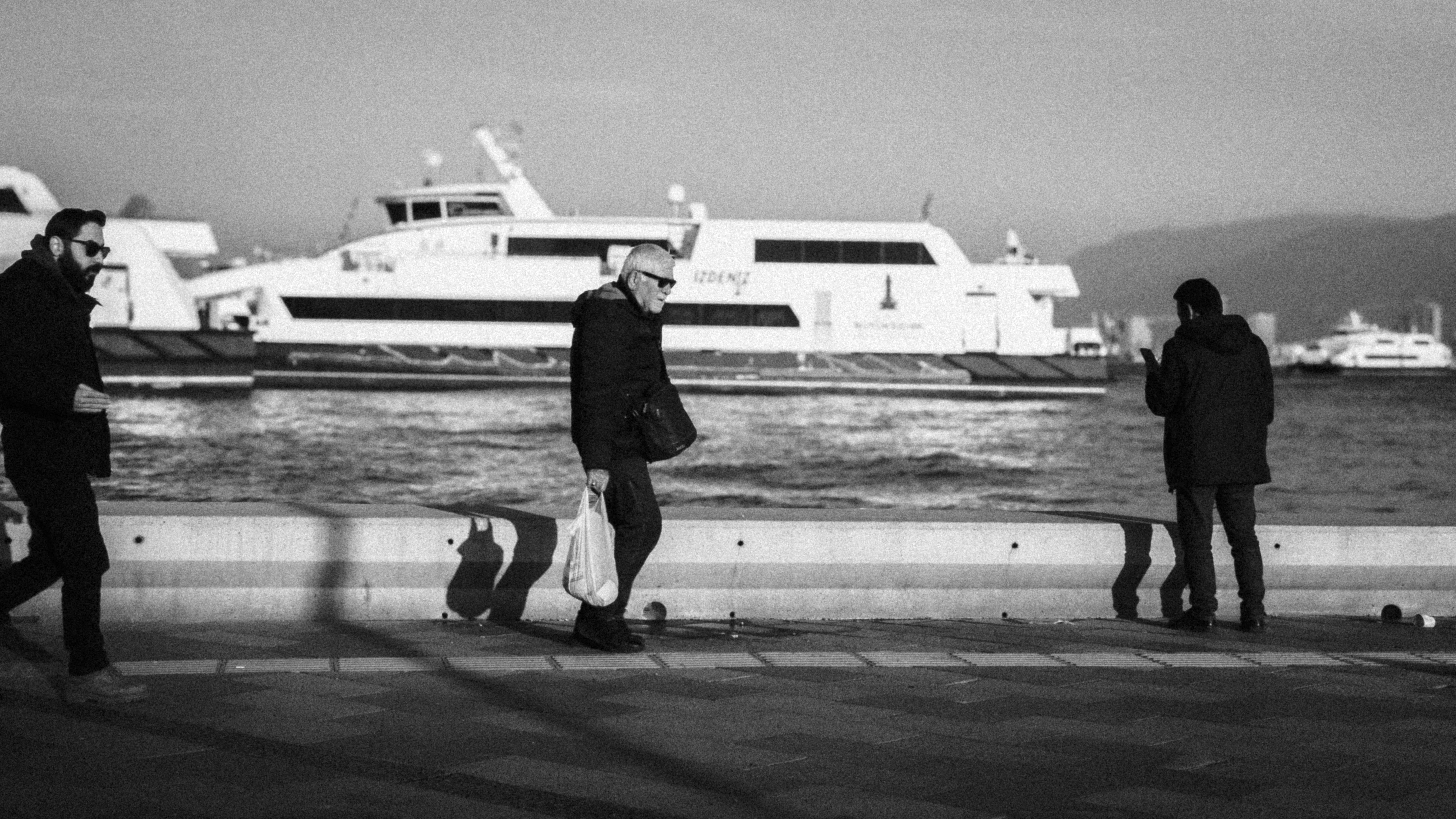 Midday Stroll by the Harbor: Figures in Shadow