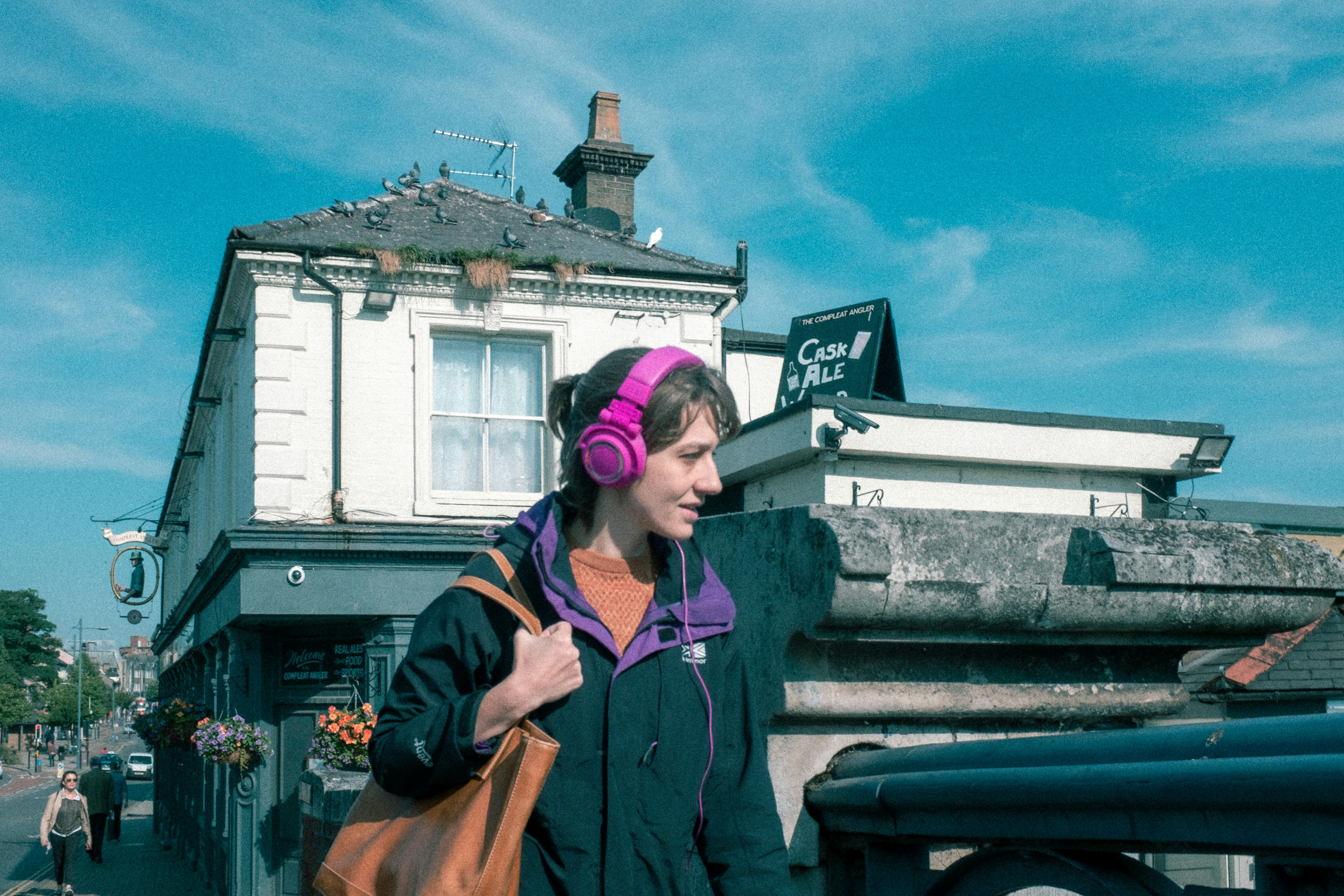City commuter with pink headphones crossing a brick-lined street
