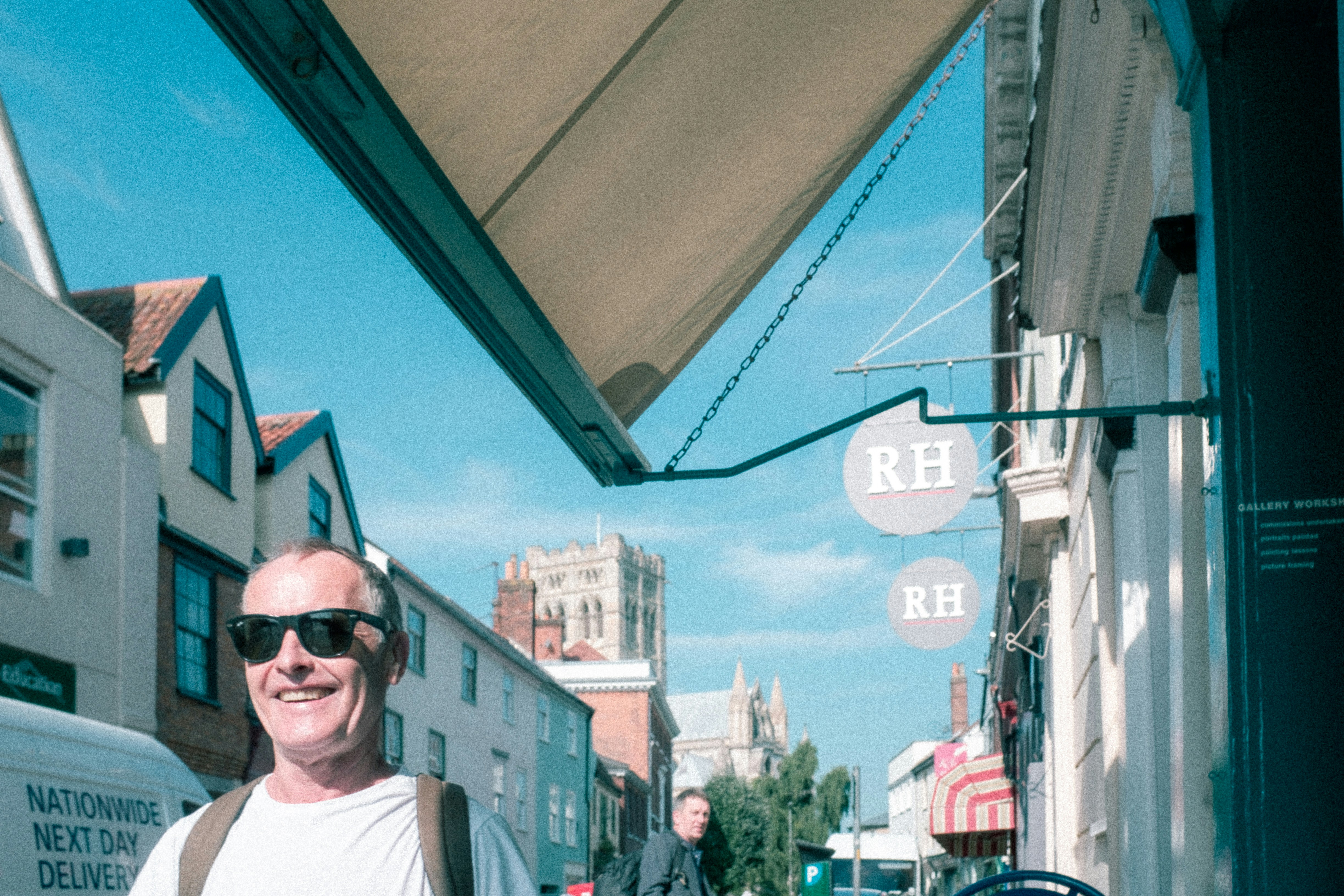 Street Portrait in Sunlit Commons: A Cheerful Stranger with Sunglasses