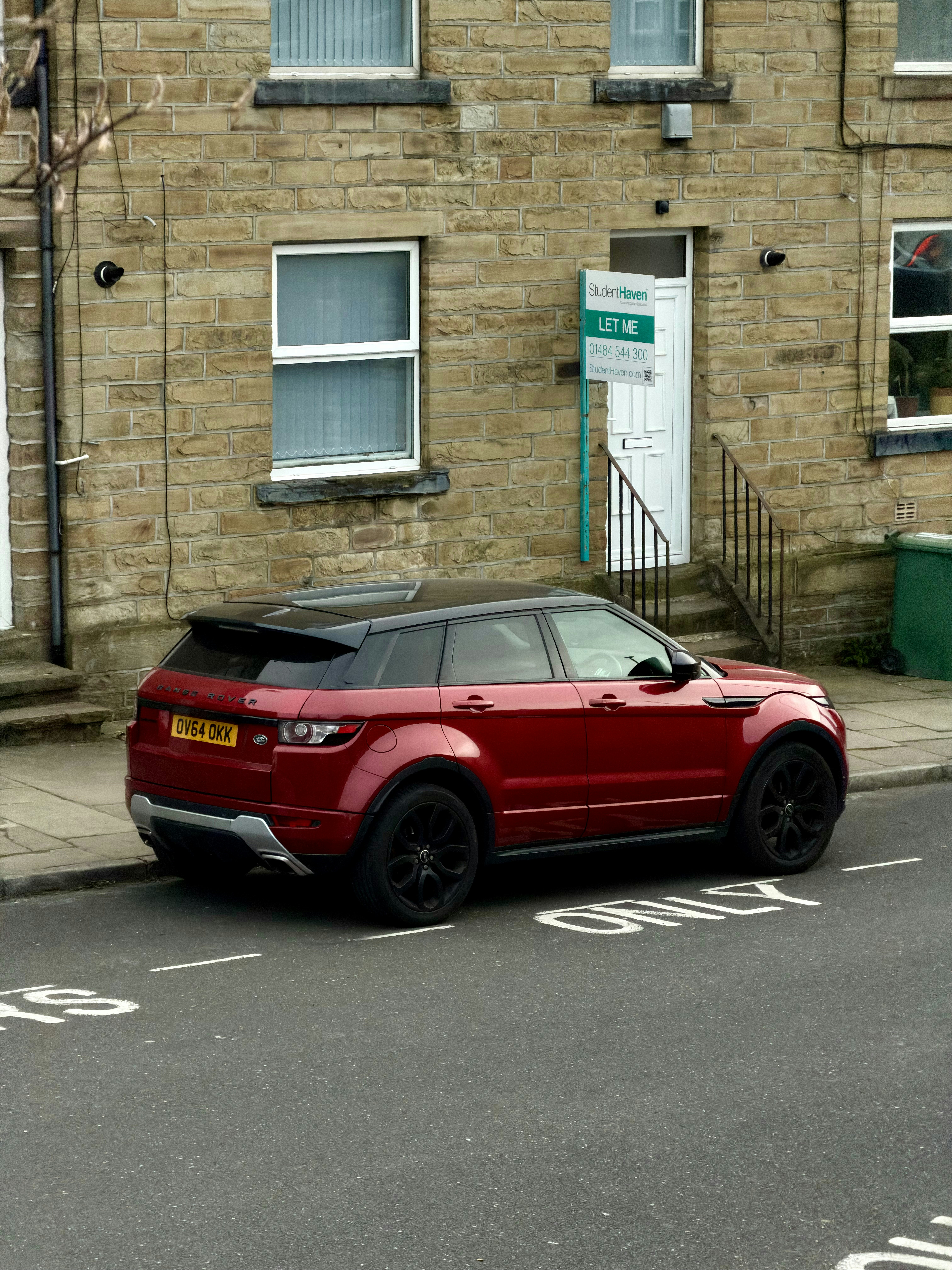 Red SUV on a Quiet Urban Street in Front of Stone Terrace