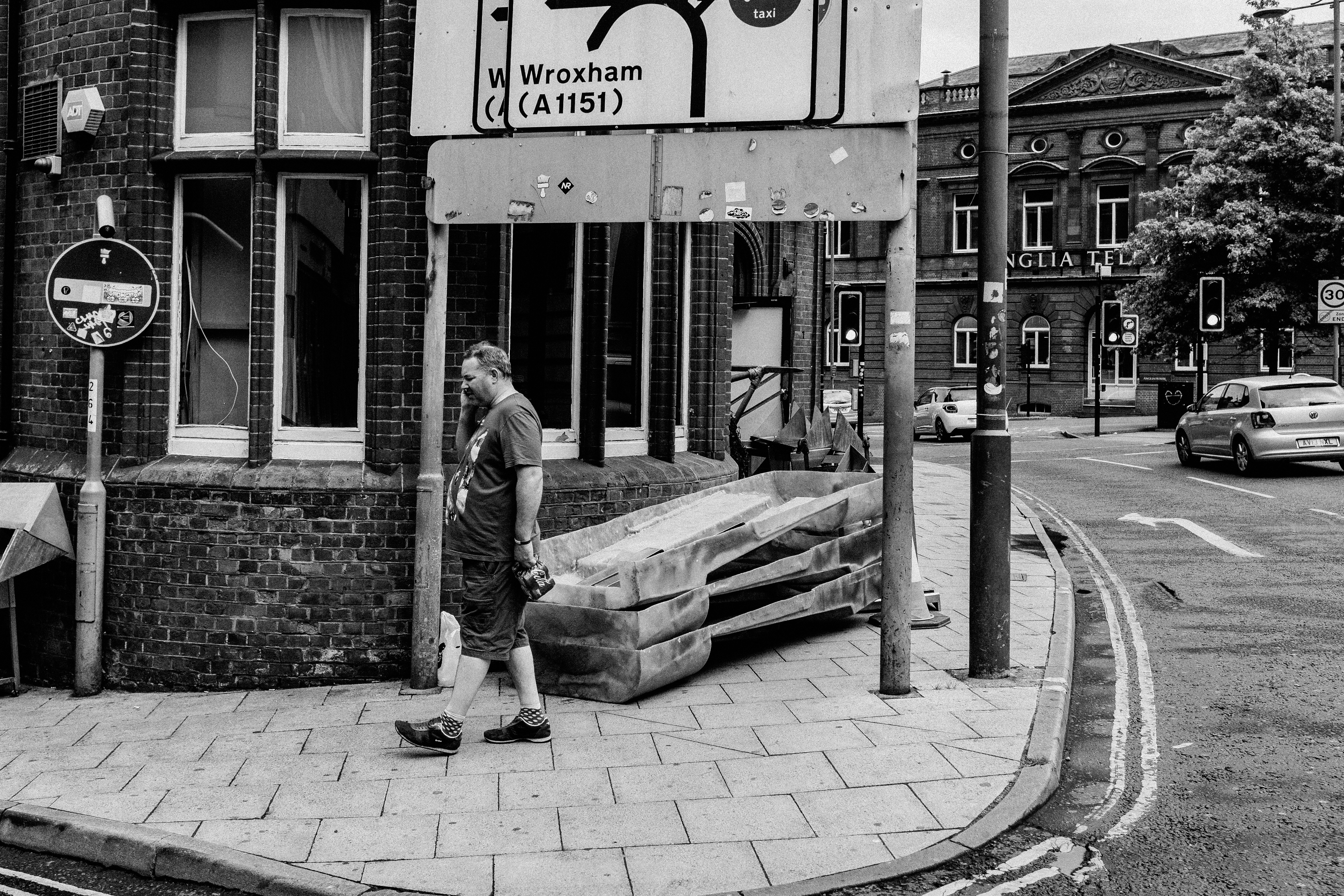 Man Crossing a City Street Beneath a Curved Road in Monochrome