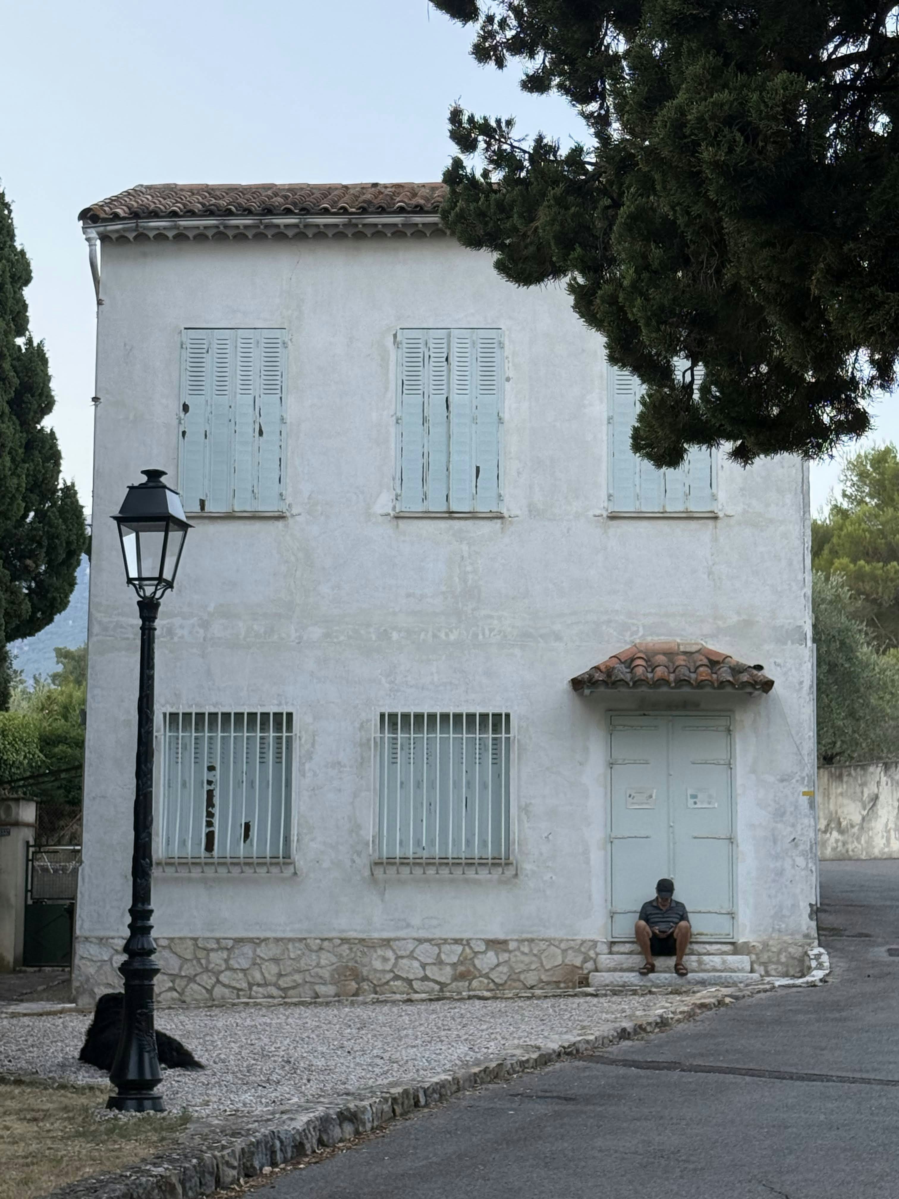 Quiet Street Facade: A White House with Blue Shutters and a Beside-Lamp