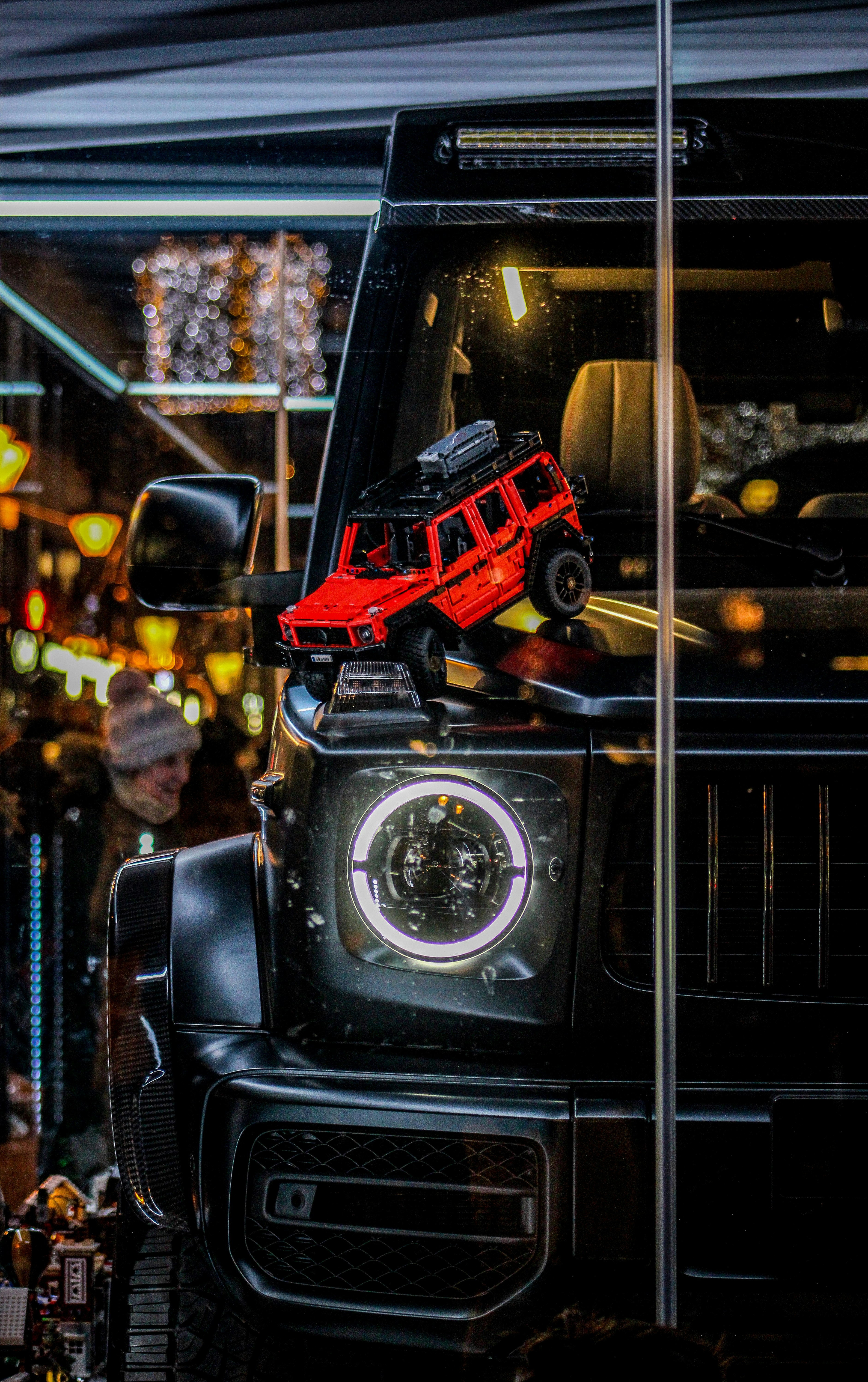 Red Adventurer on the Glass: A Jeep Toy Guards the Headlight