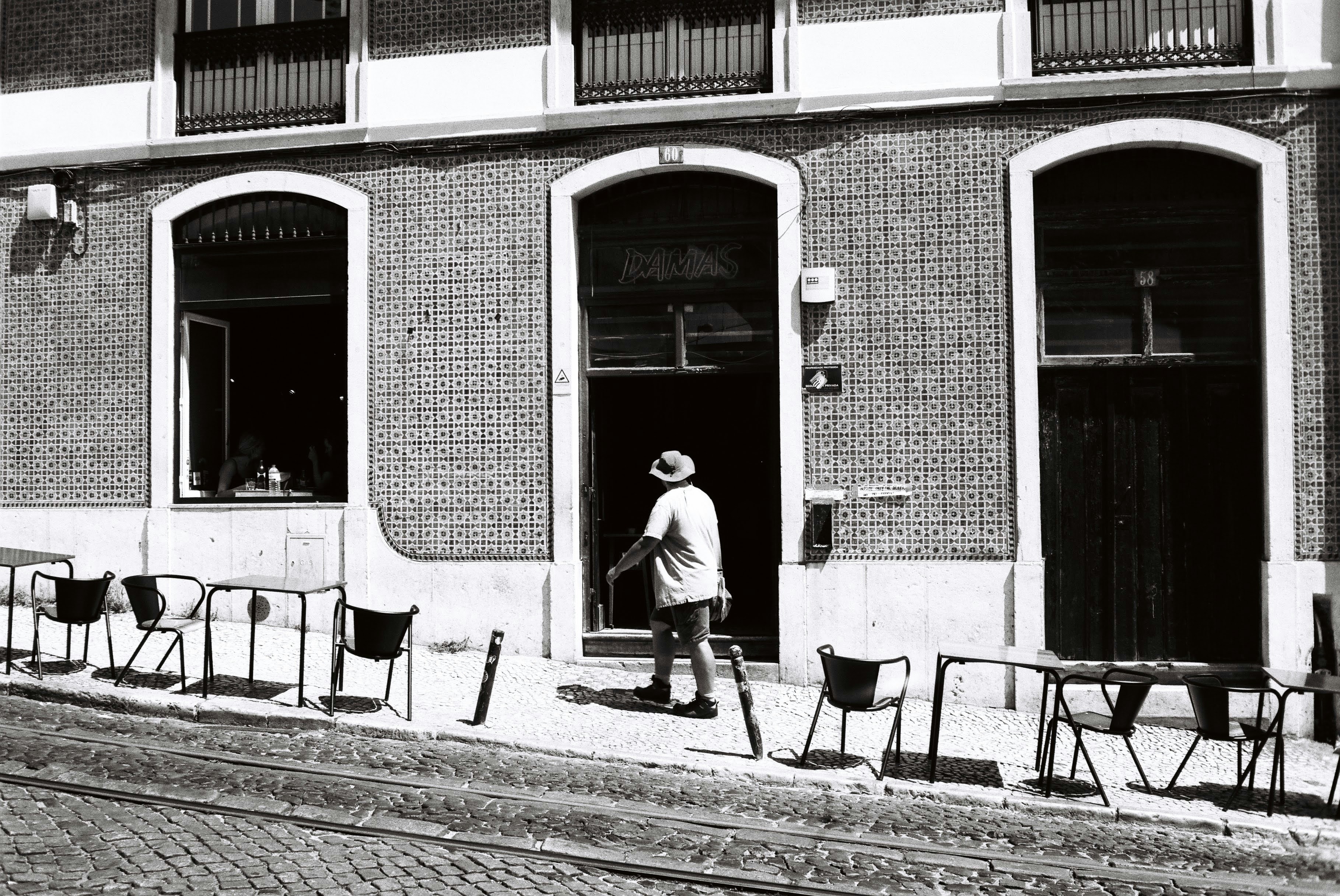 Passing Through: A lone walker amid café-lined brick facade