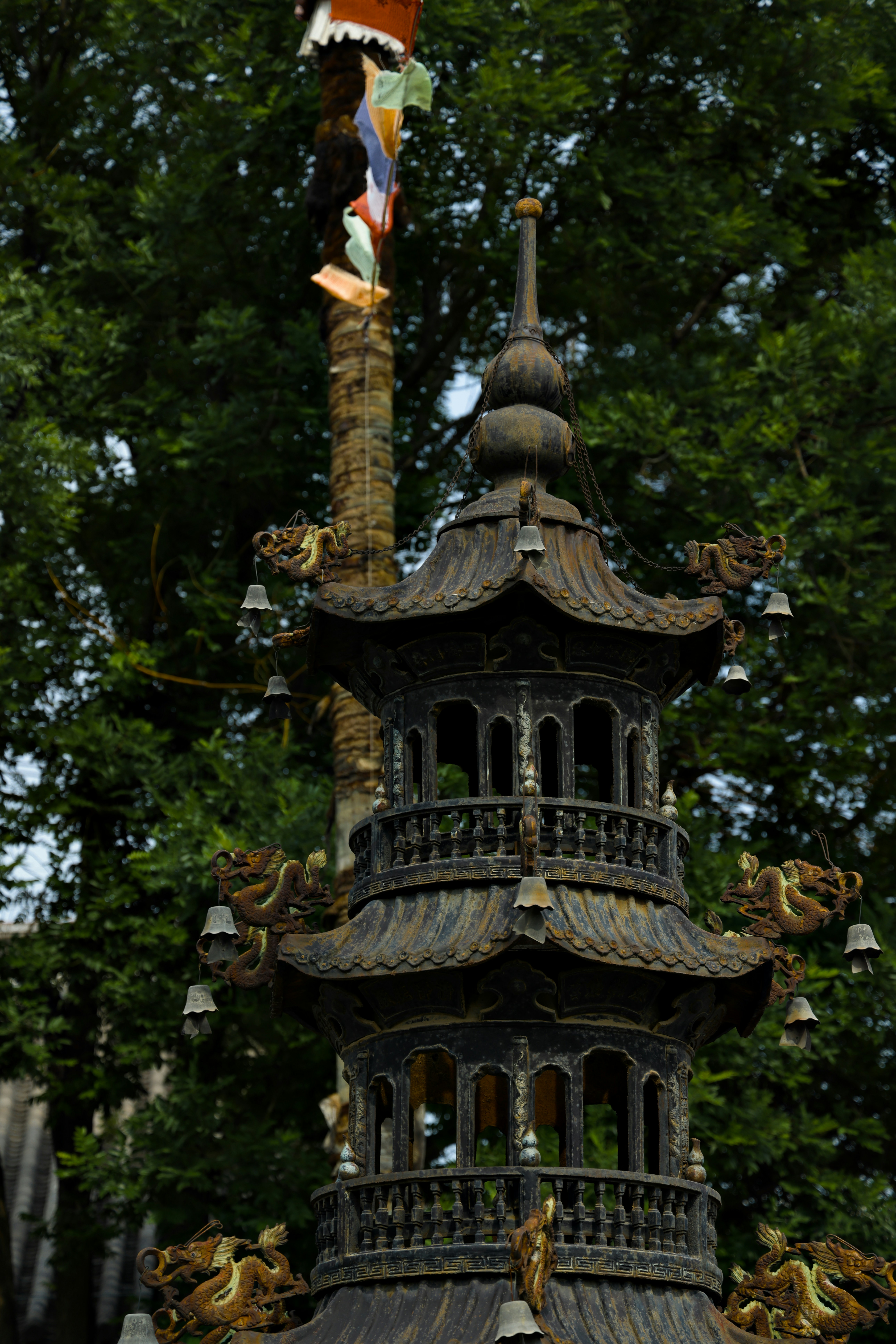 Heritage Lantern Tower: Weathered Dragon Carvings Amid Green Canopy
