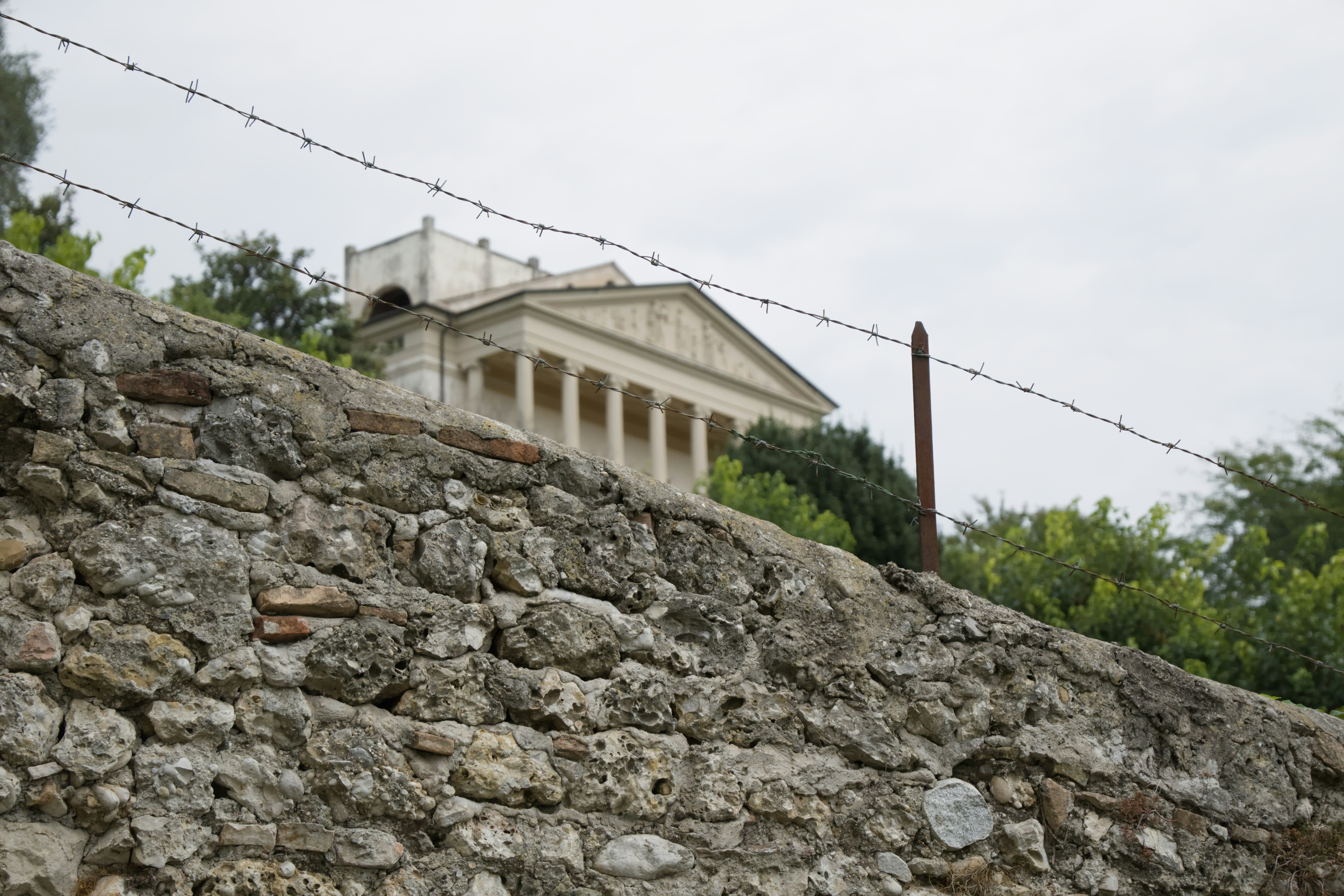 Ancient Wall, Classical Facade, and Barbed Sky