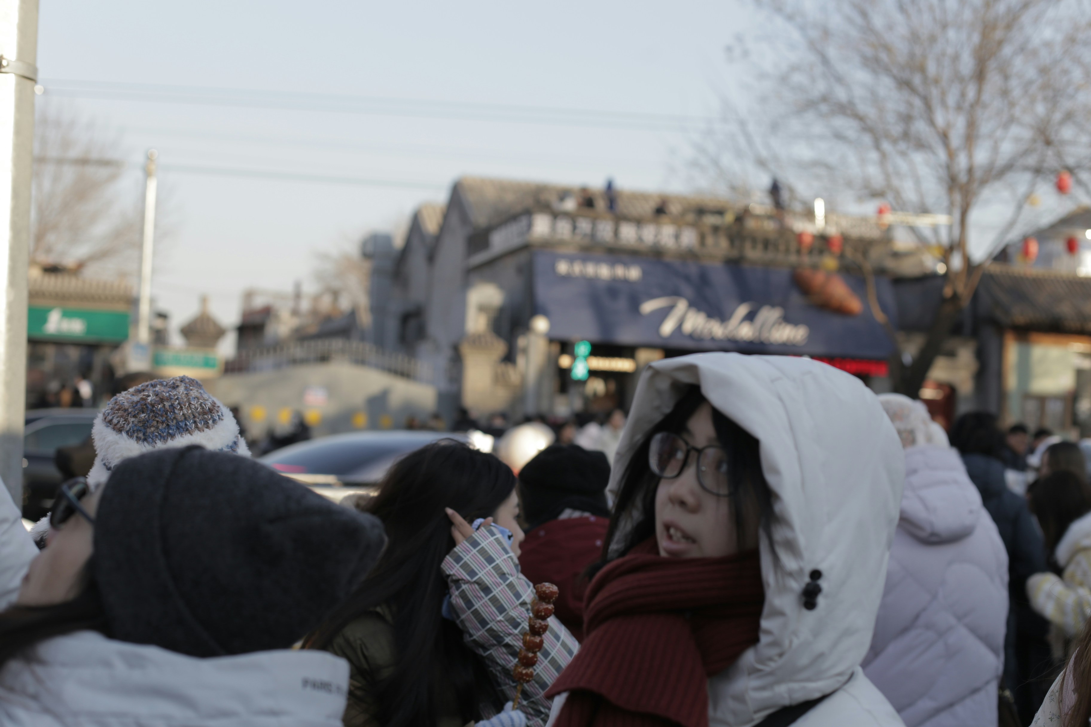 Crowded Street Scene with Central Figure in White Hood