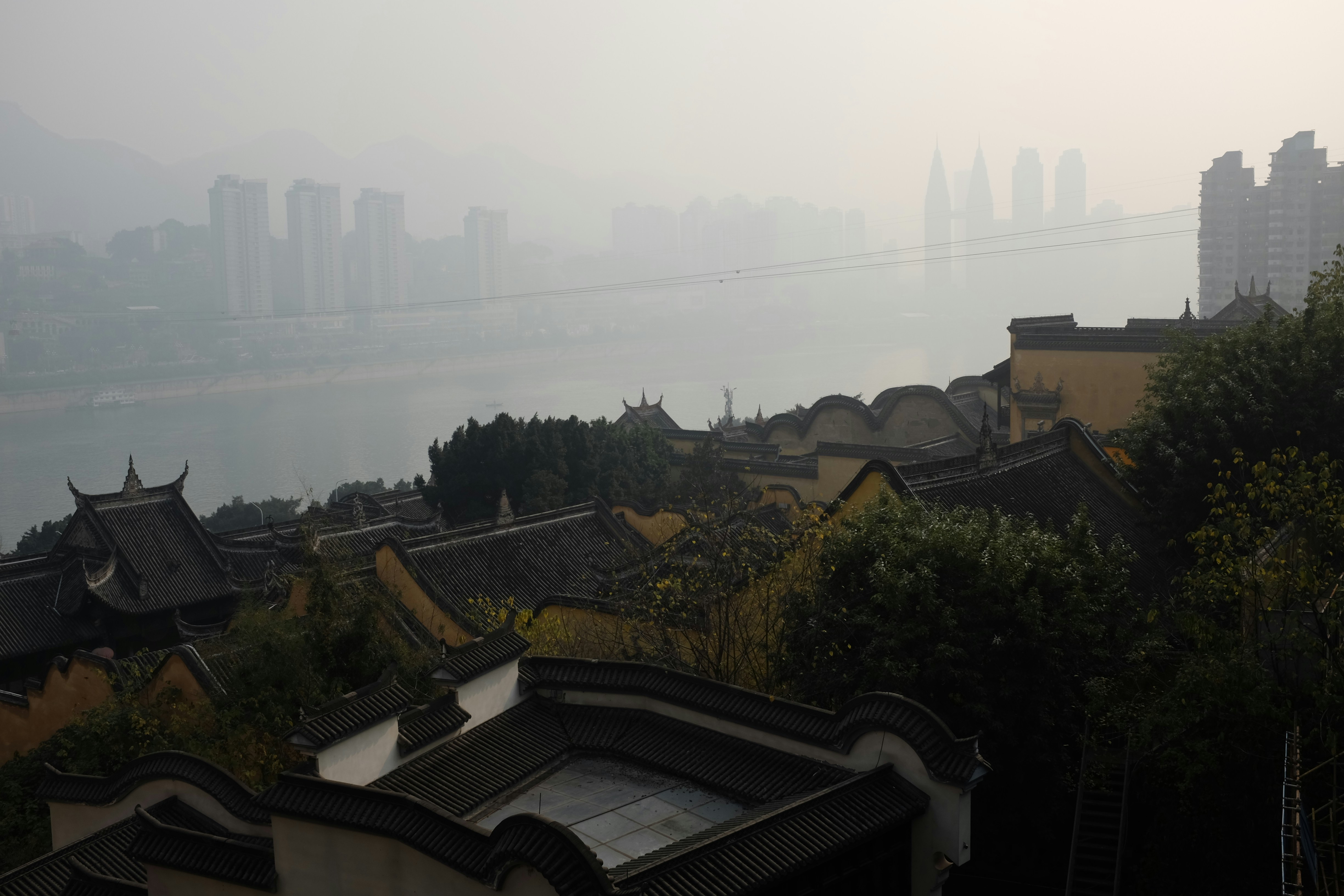 Mist over the river: traditional rooftops meet a distant skyline