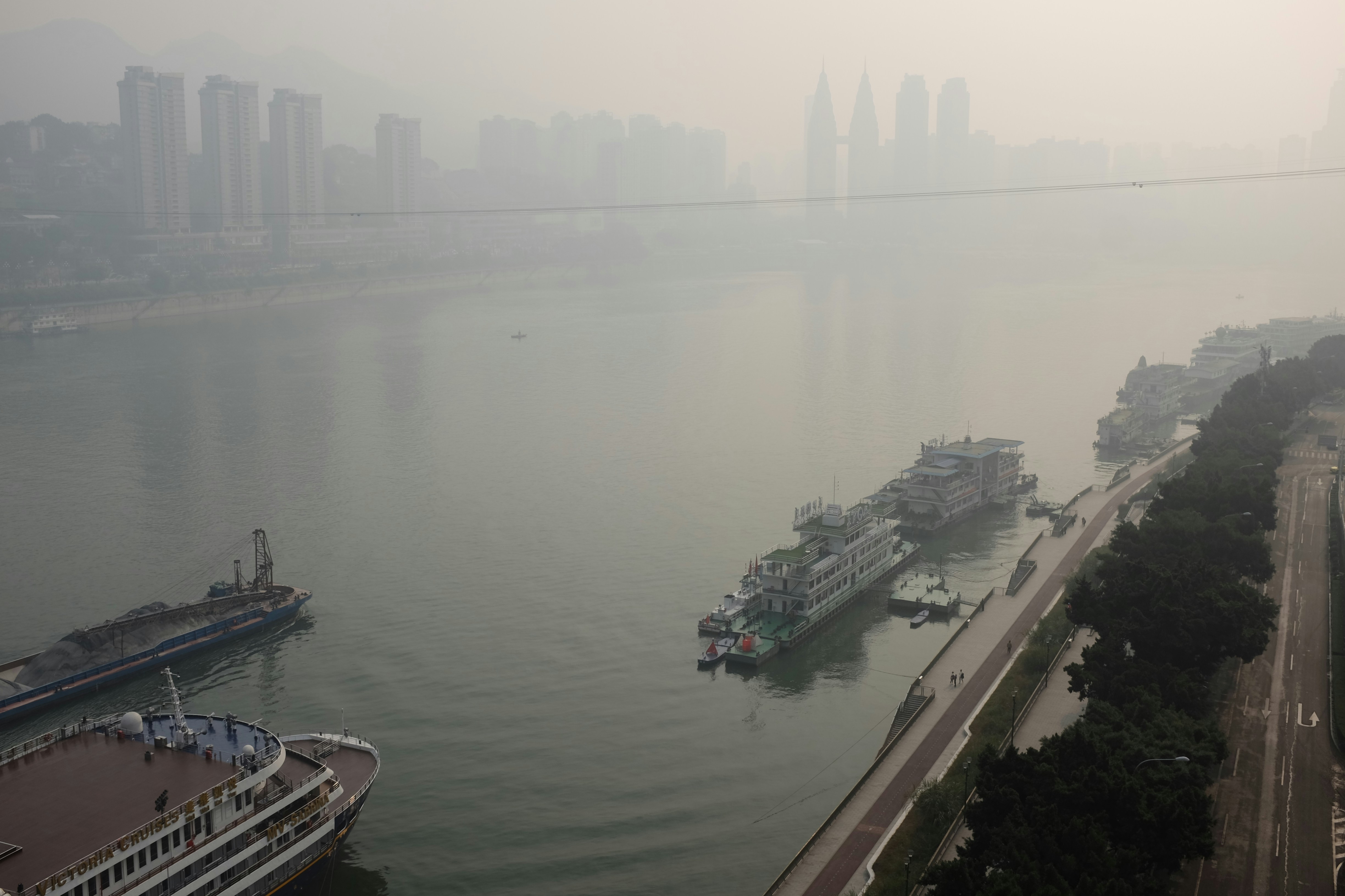 Harbor in Haze: Boats and Riverfront Under Overcast Skies