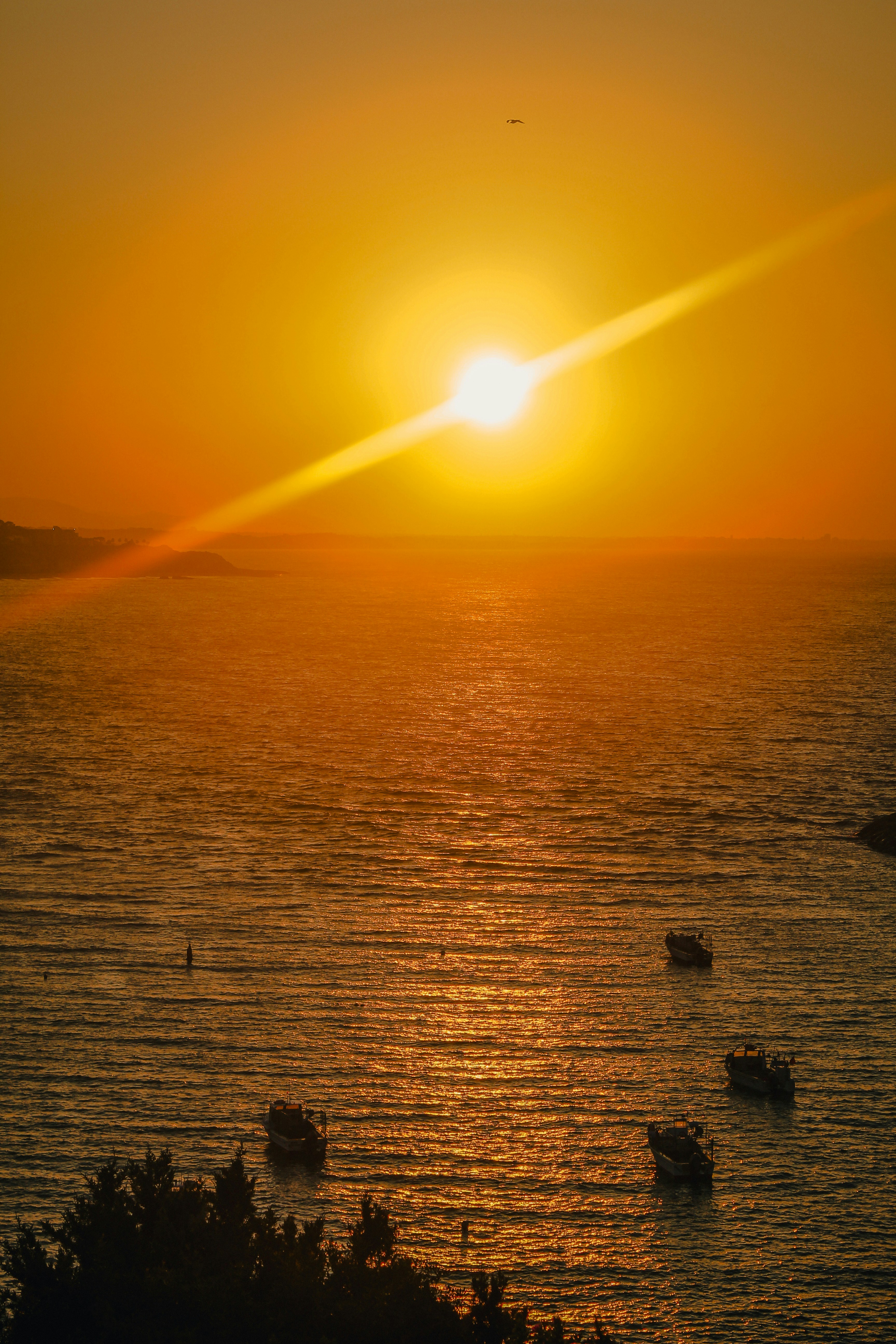 Sunlit Horizon: Boats at Dusk Under a Golden Flare