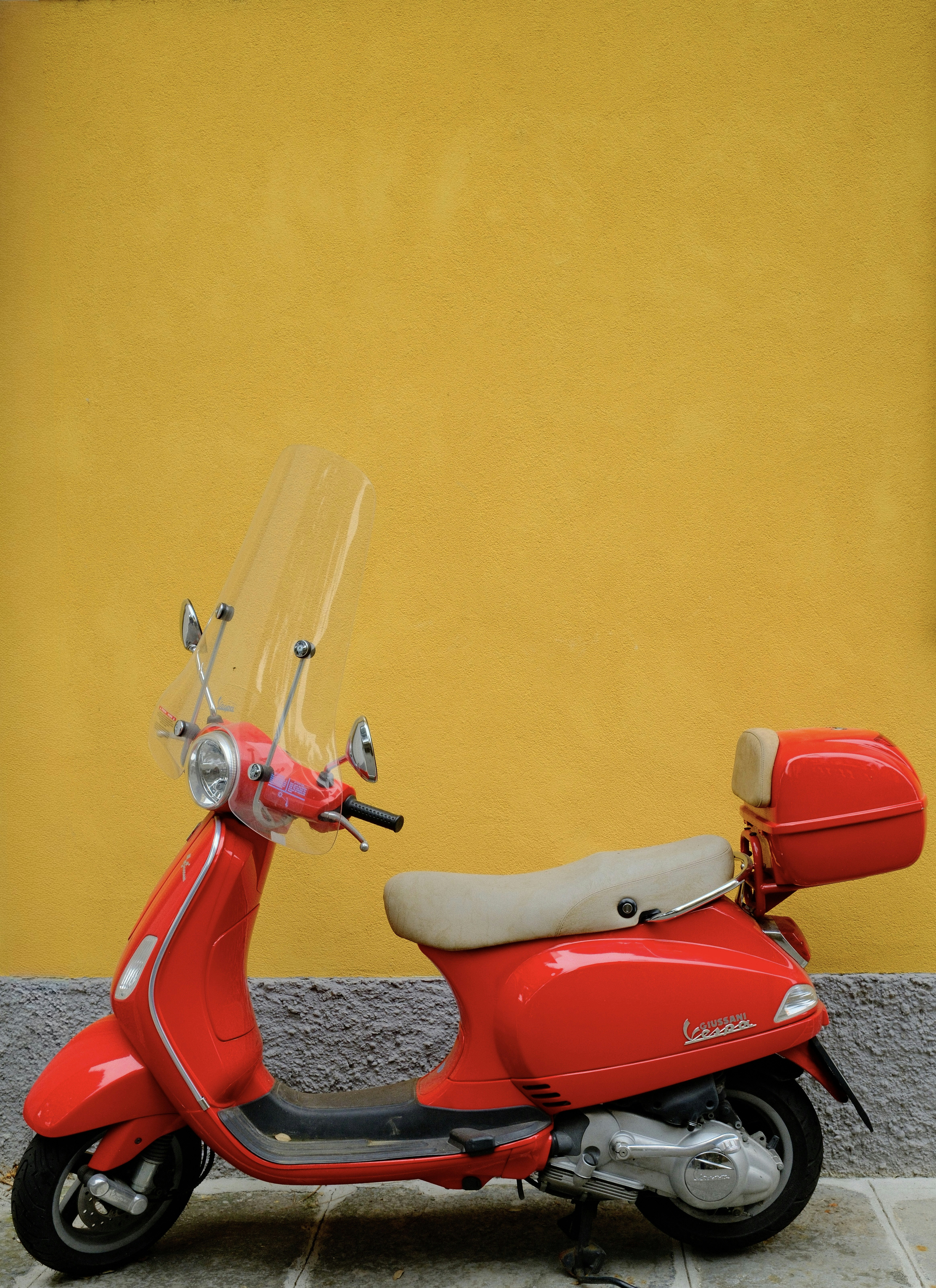 Red Classic: A Vespa Resting Against a Golden Wall
