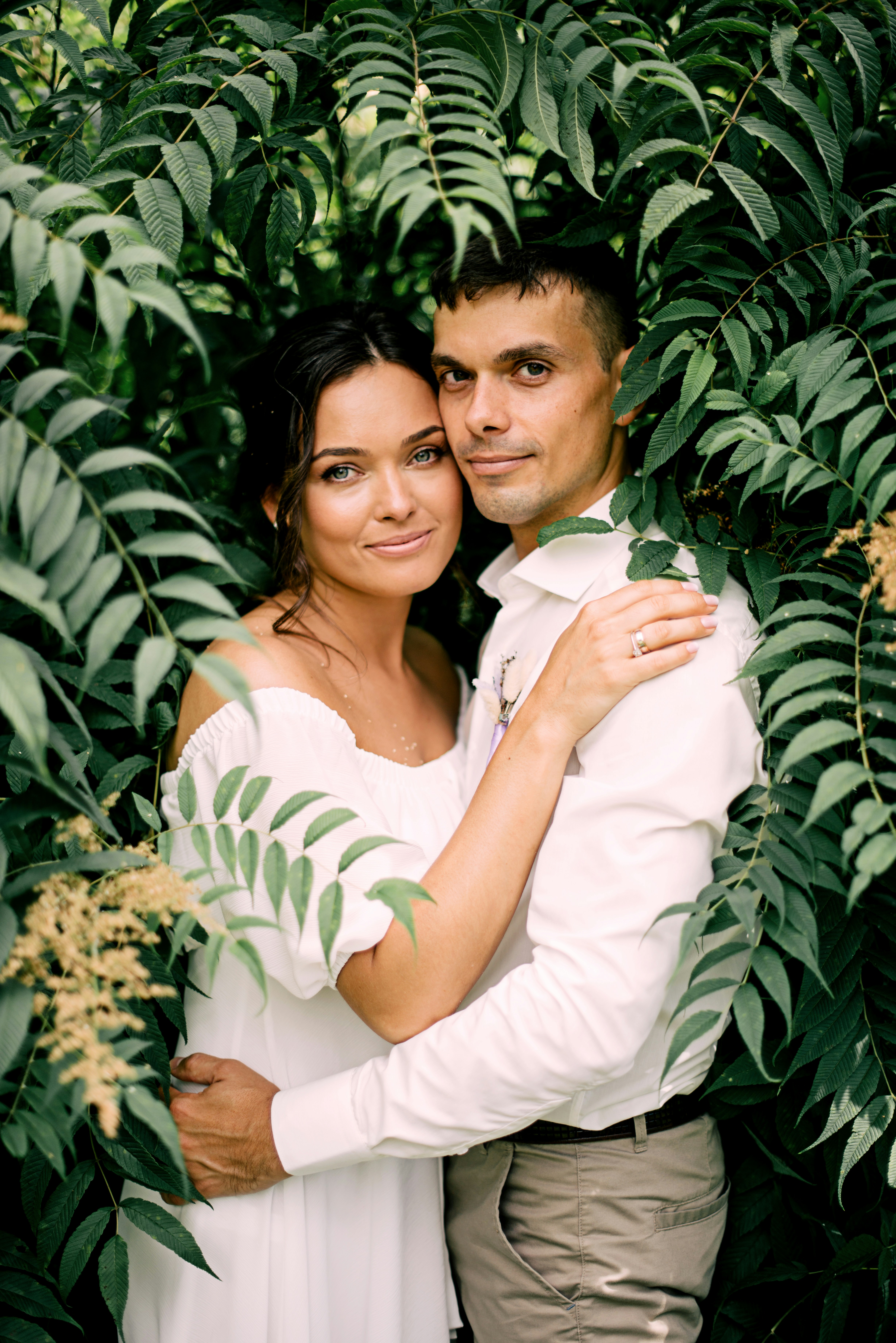 Close embraced in verde: a couple framed by leafy tendrils