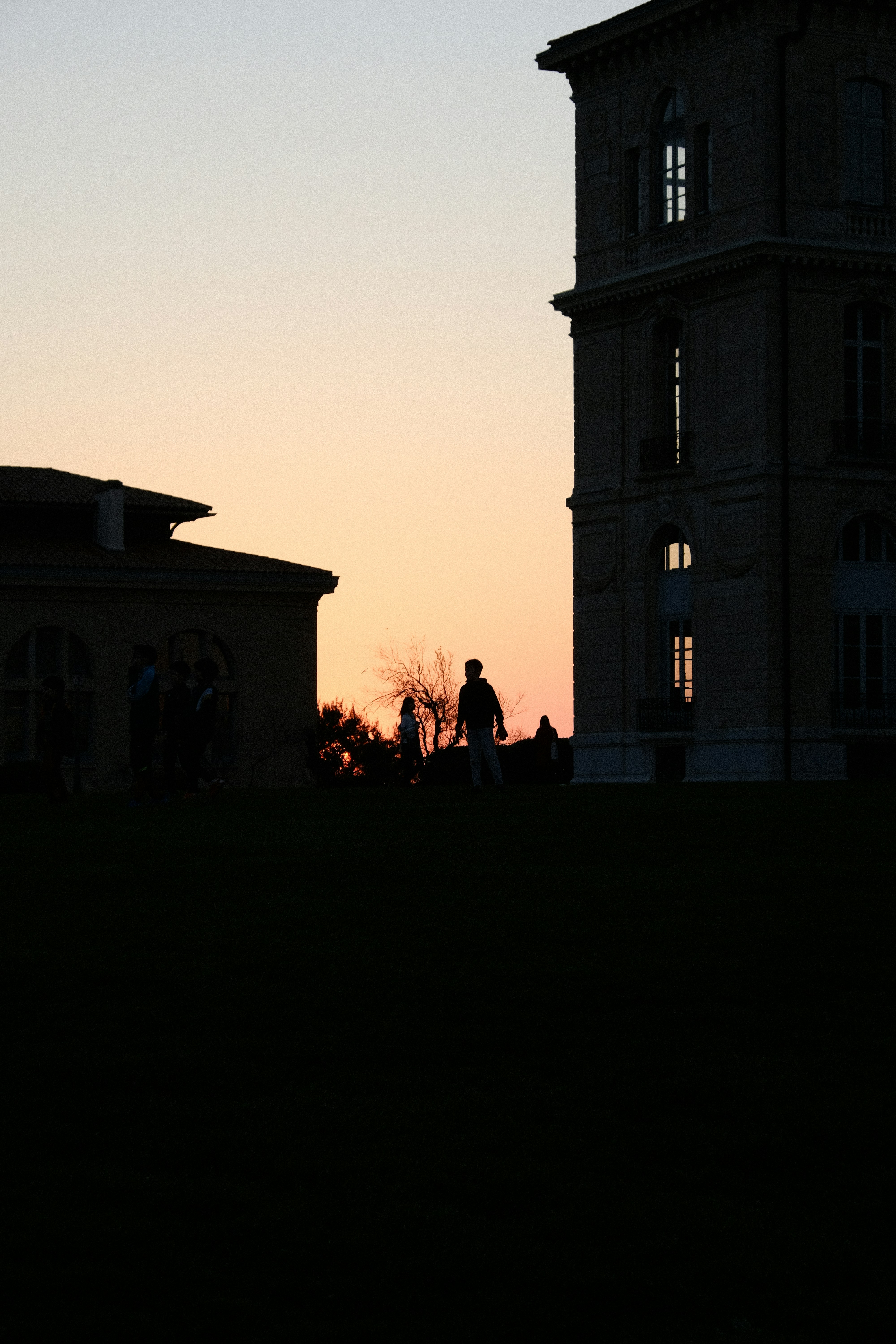 Silhouetted Figures at Sunset by the Historic Tower
