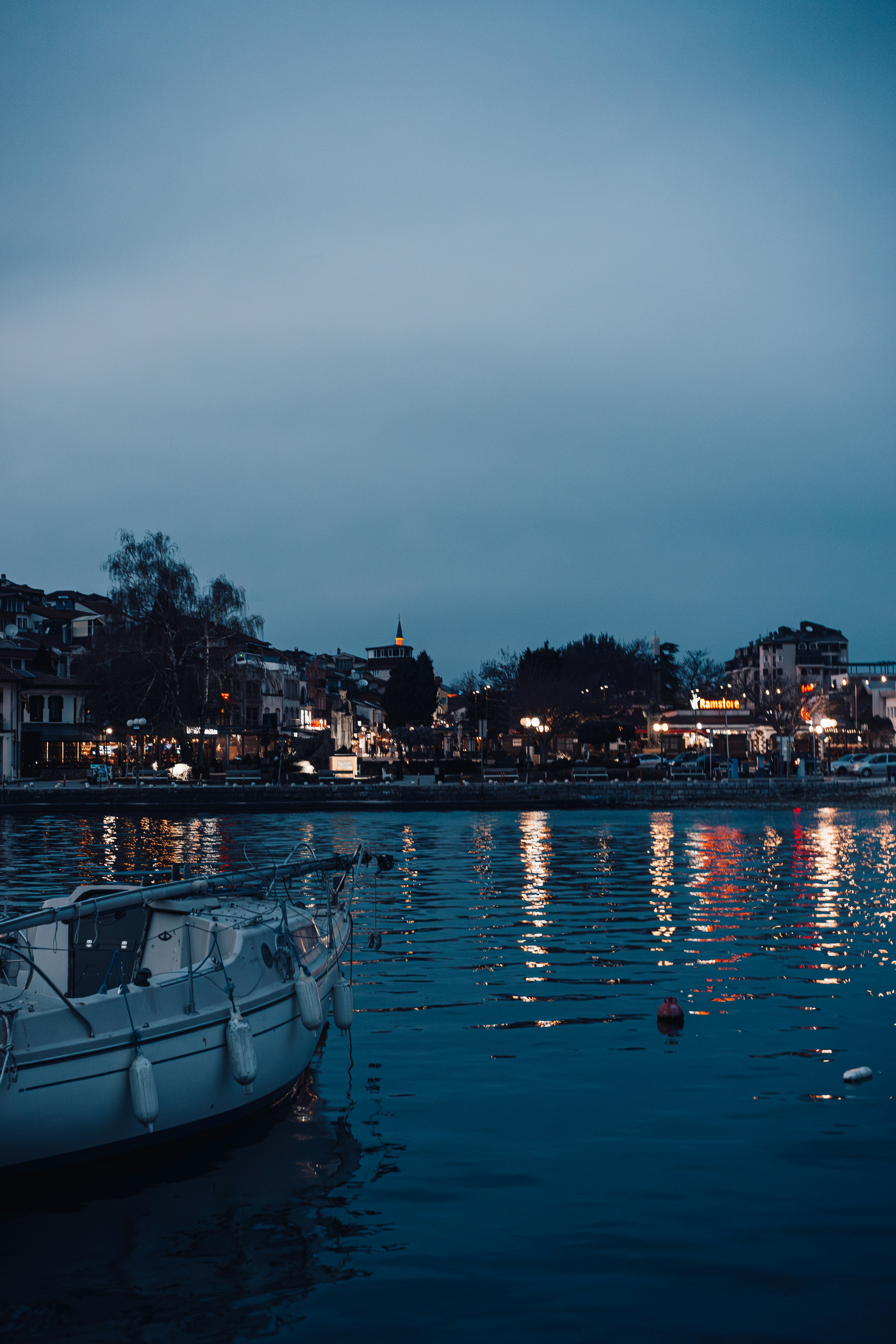 Quiet Lakeside Evening: Boats, Lights, and a Distant Town