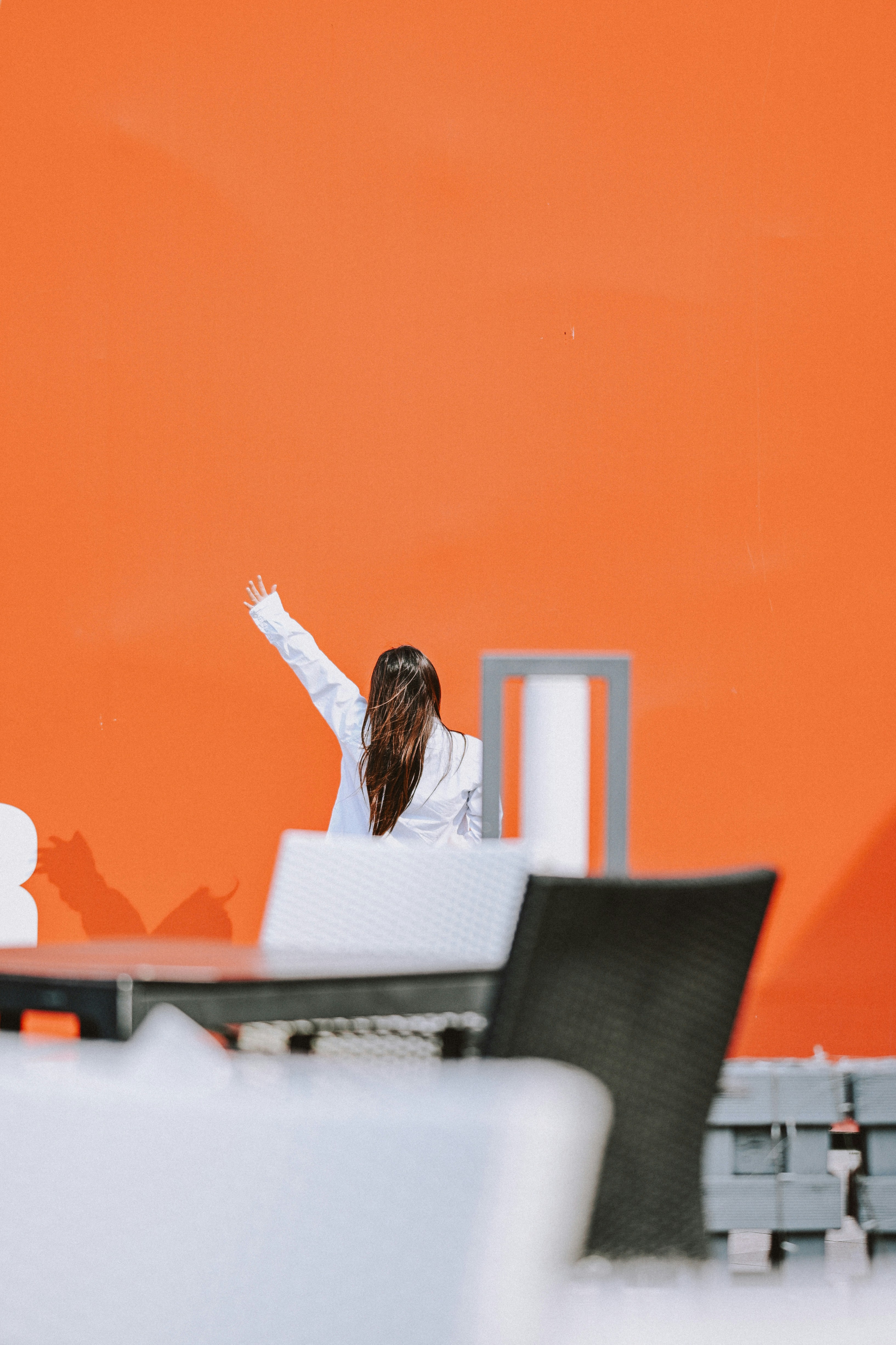 Wave of Orange: Figure with Raised Hand in Bright Backdrop