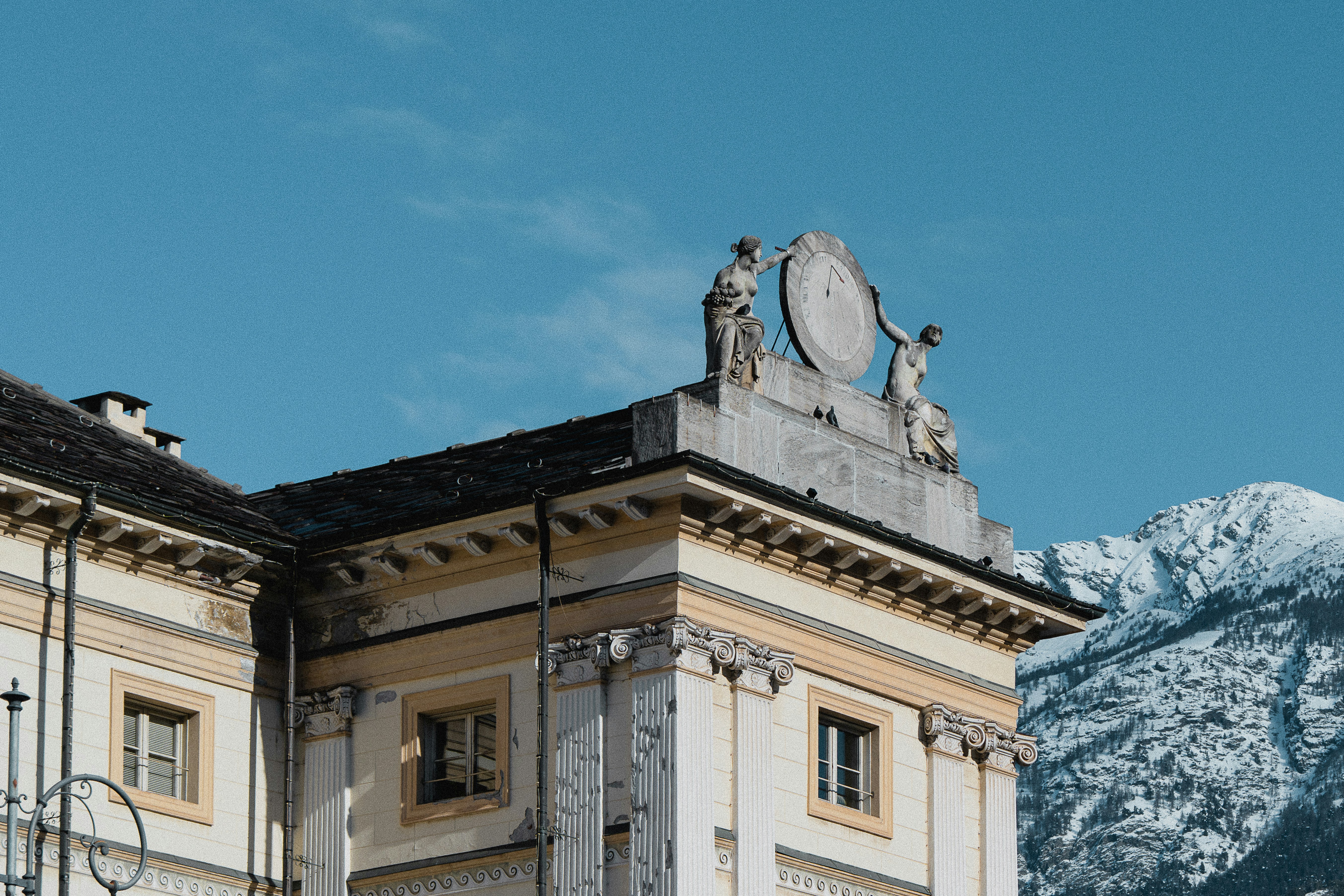 Classical Facade crowned by Sculpted Clock and Alpine Backdrop