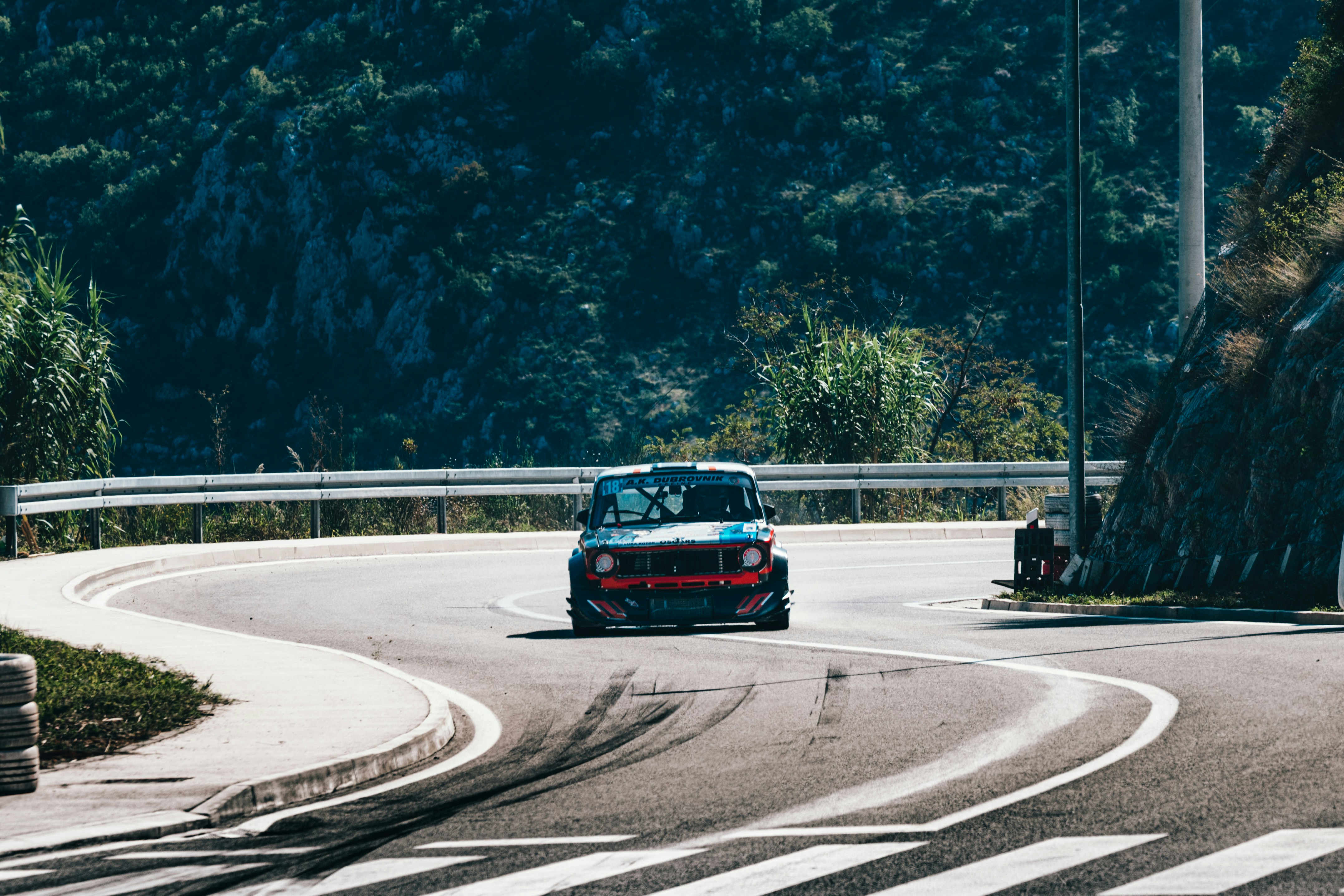 Curved Asphalt Racer: A classic red coupe Navigates a Twilight Hairpin