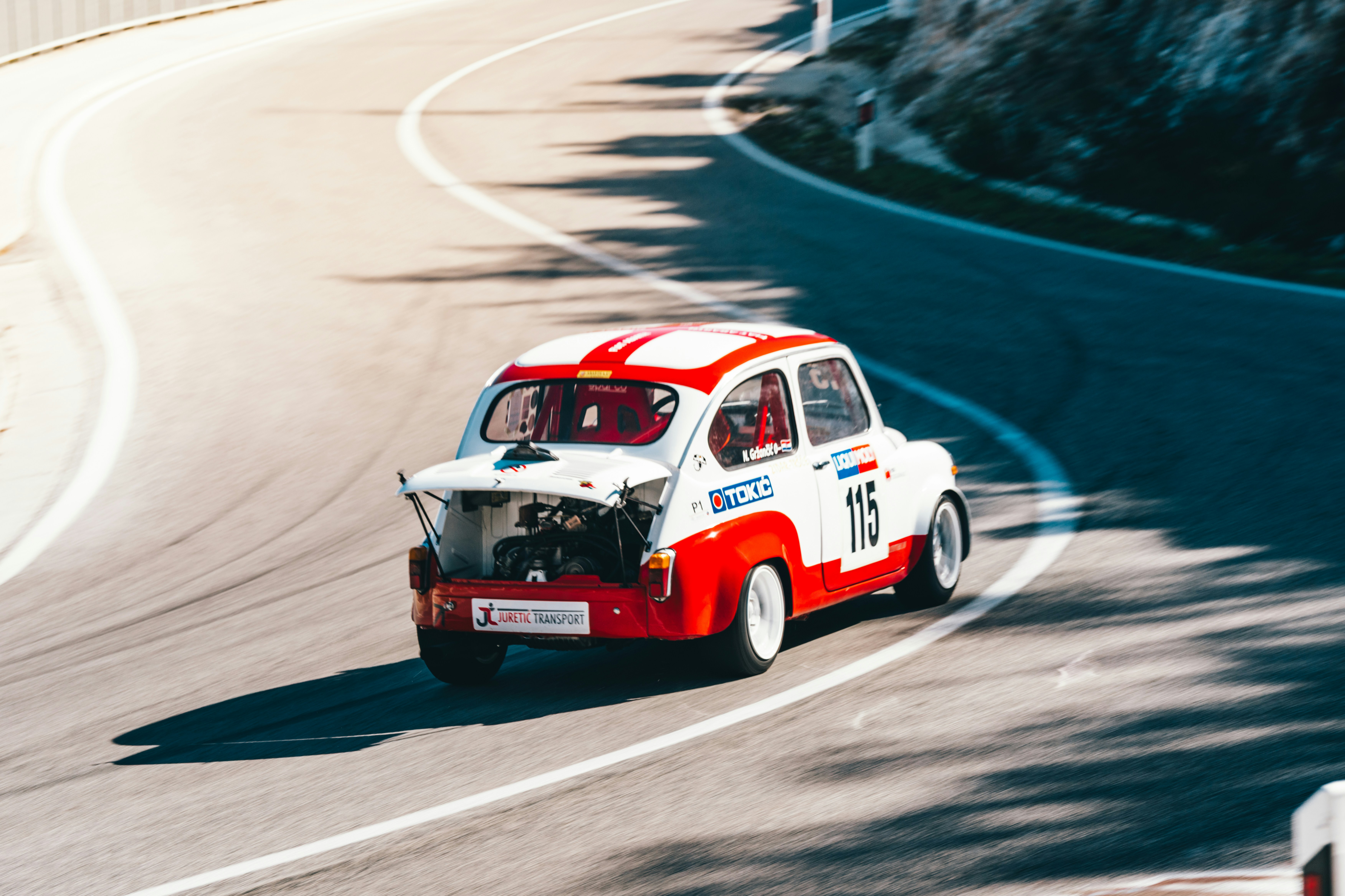 Red-and-White Rally Hero Navigates a Sunlit Hairpin