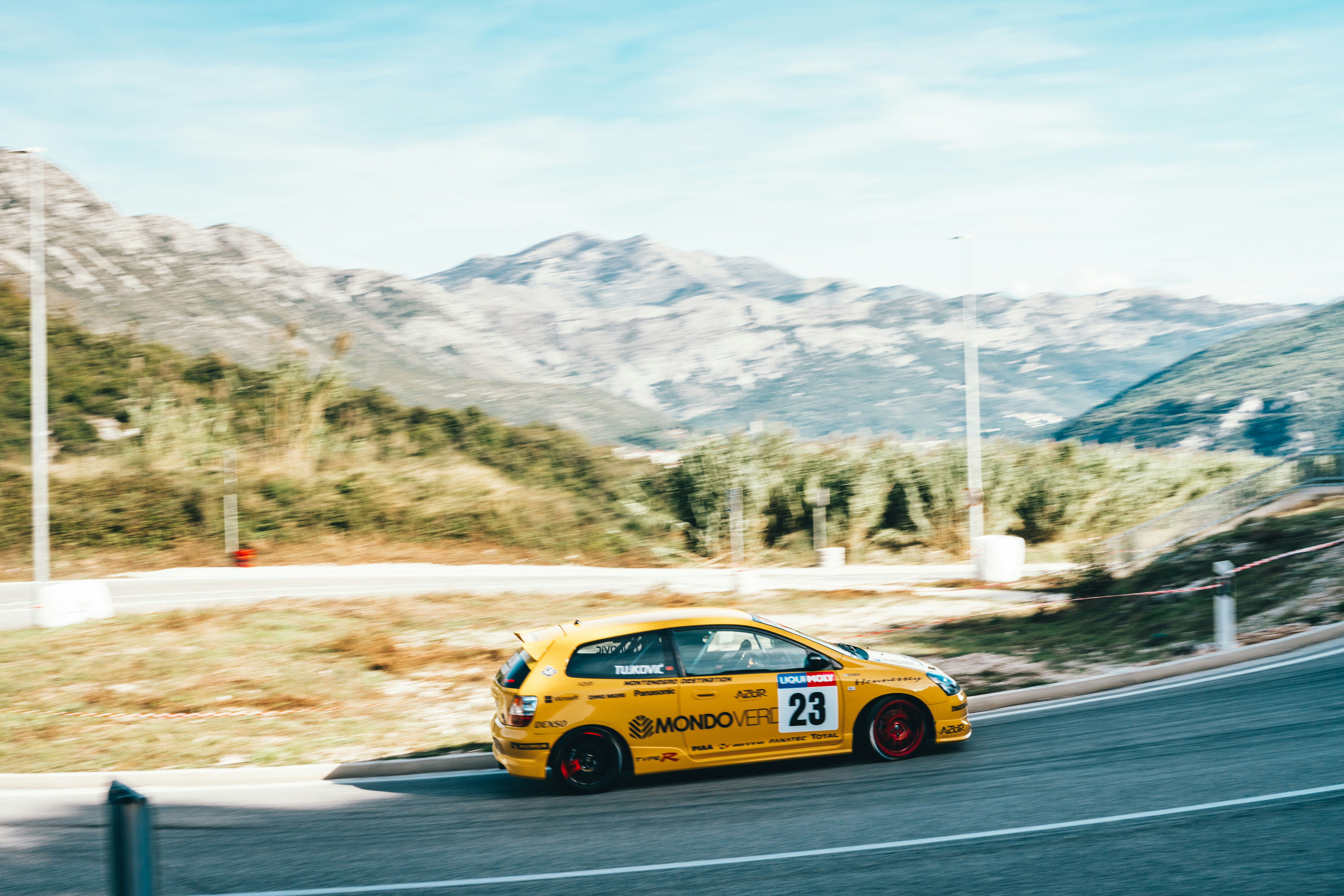 Yellow Race Car Navigates a Mountain Curve