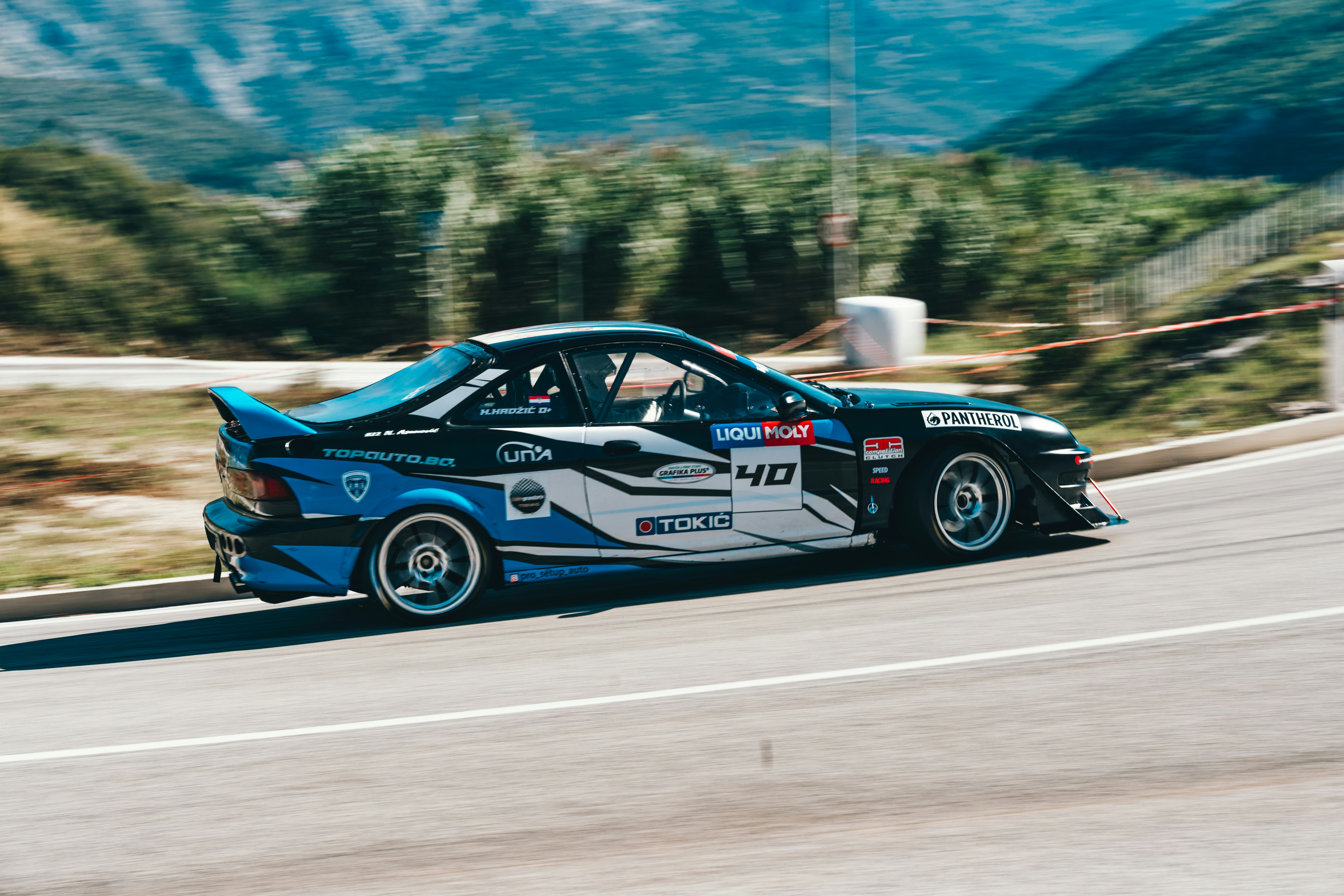 Blitz on Asphalt: Blue-and-White Race Car In Fast Pursuit