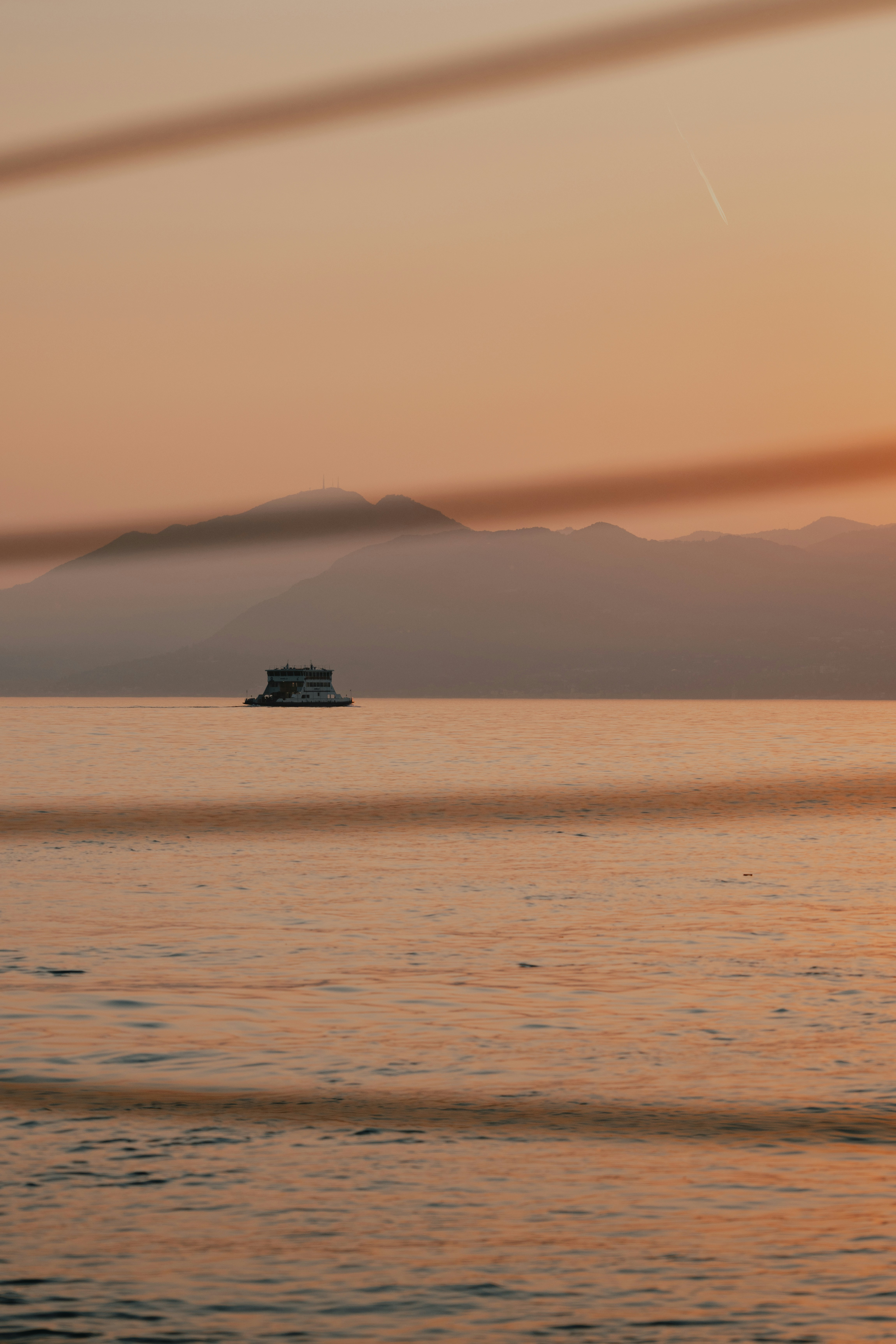 Muted Horizon: A Sea Vessel Amid Cascade Mountains at Dusk