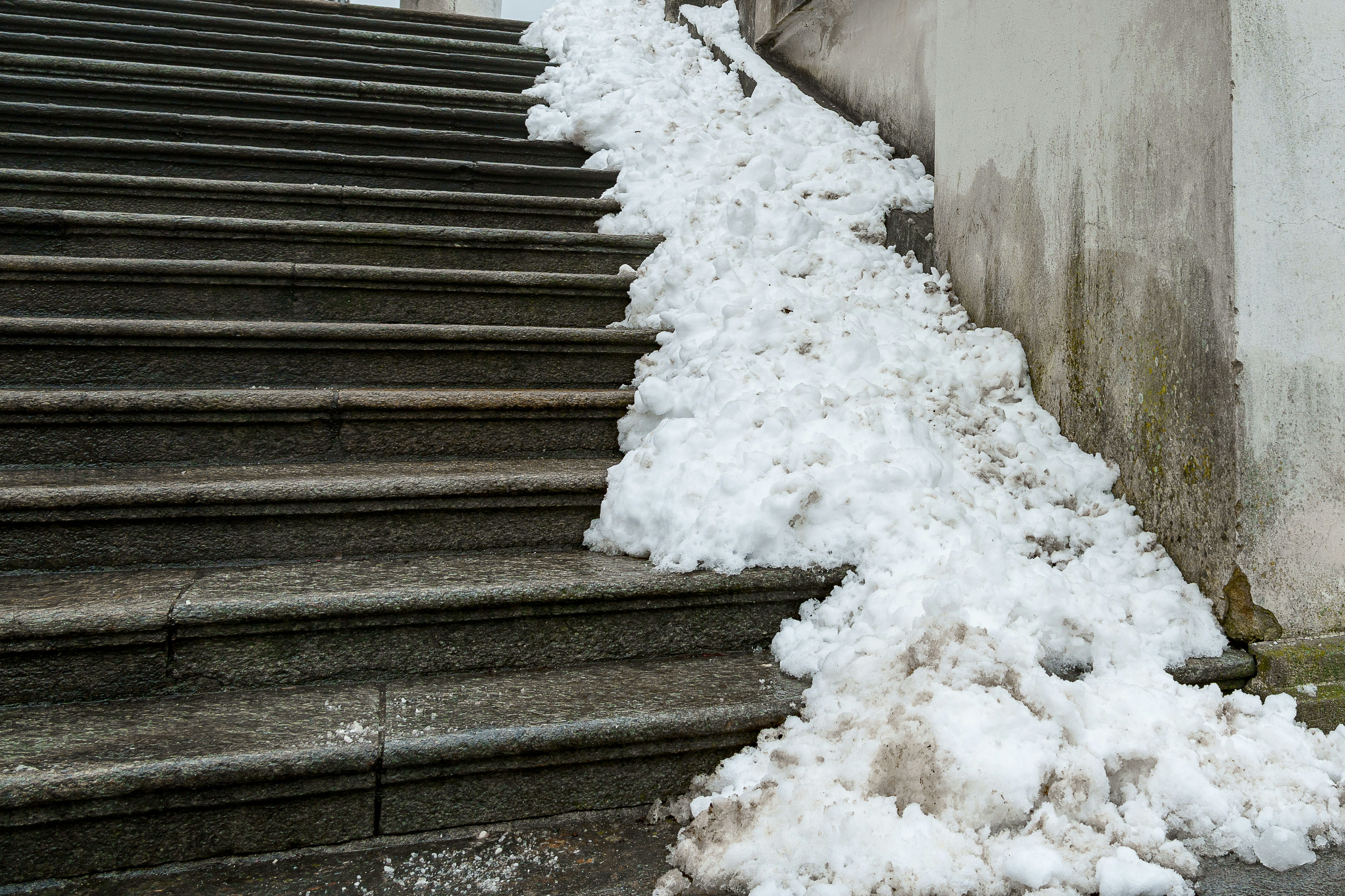 Snow around a concrete stairway scarred by time