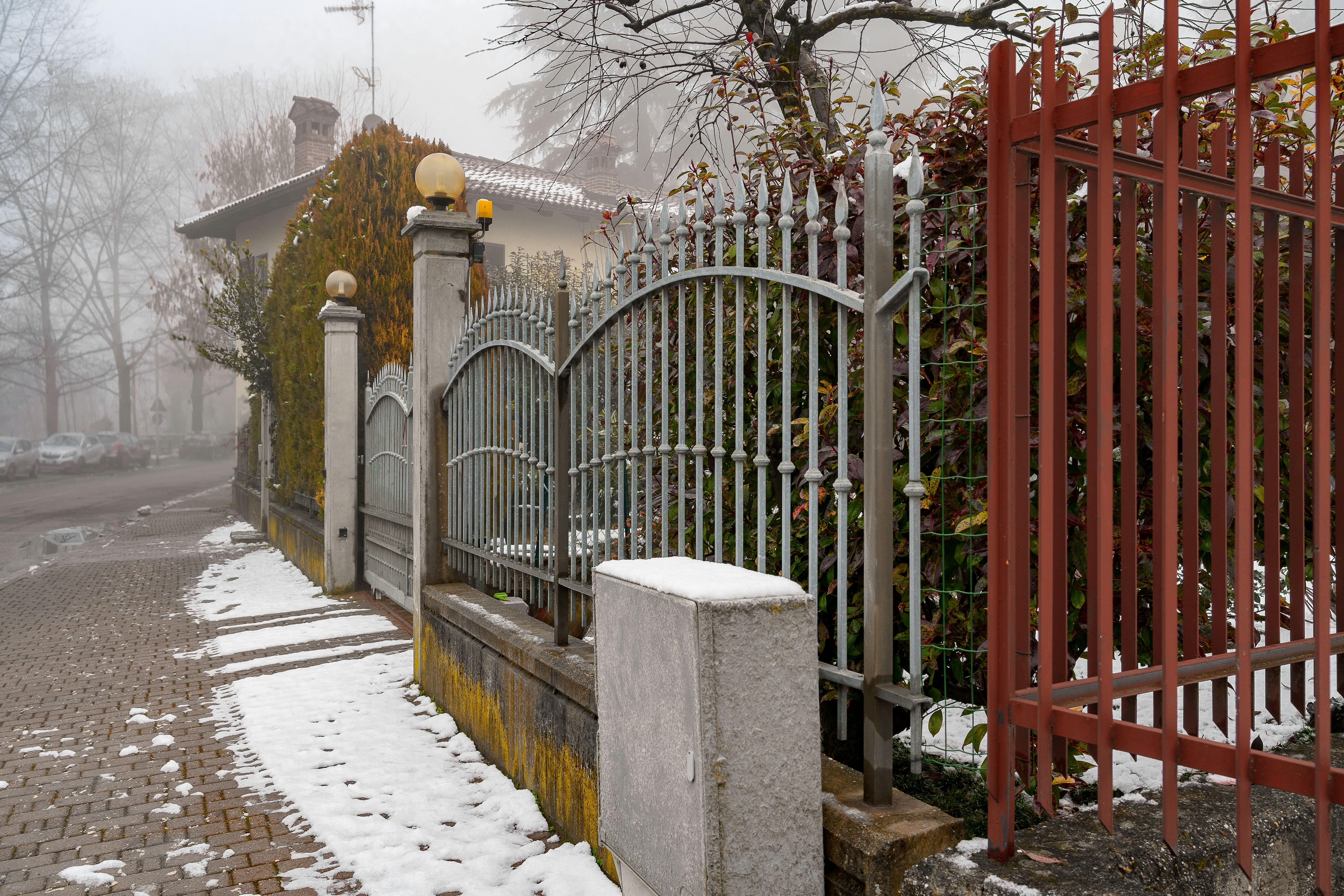 Snowy courtyard fence leading to a foggy street