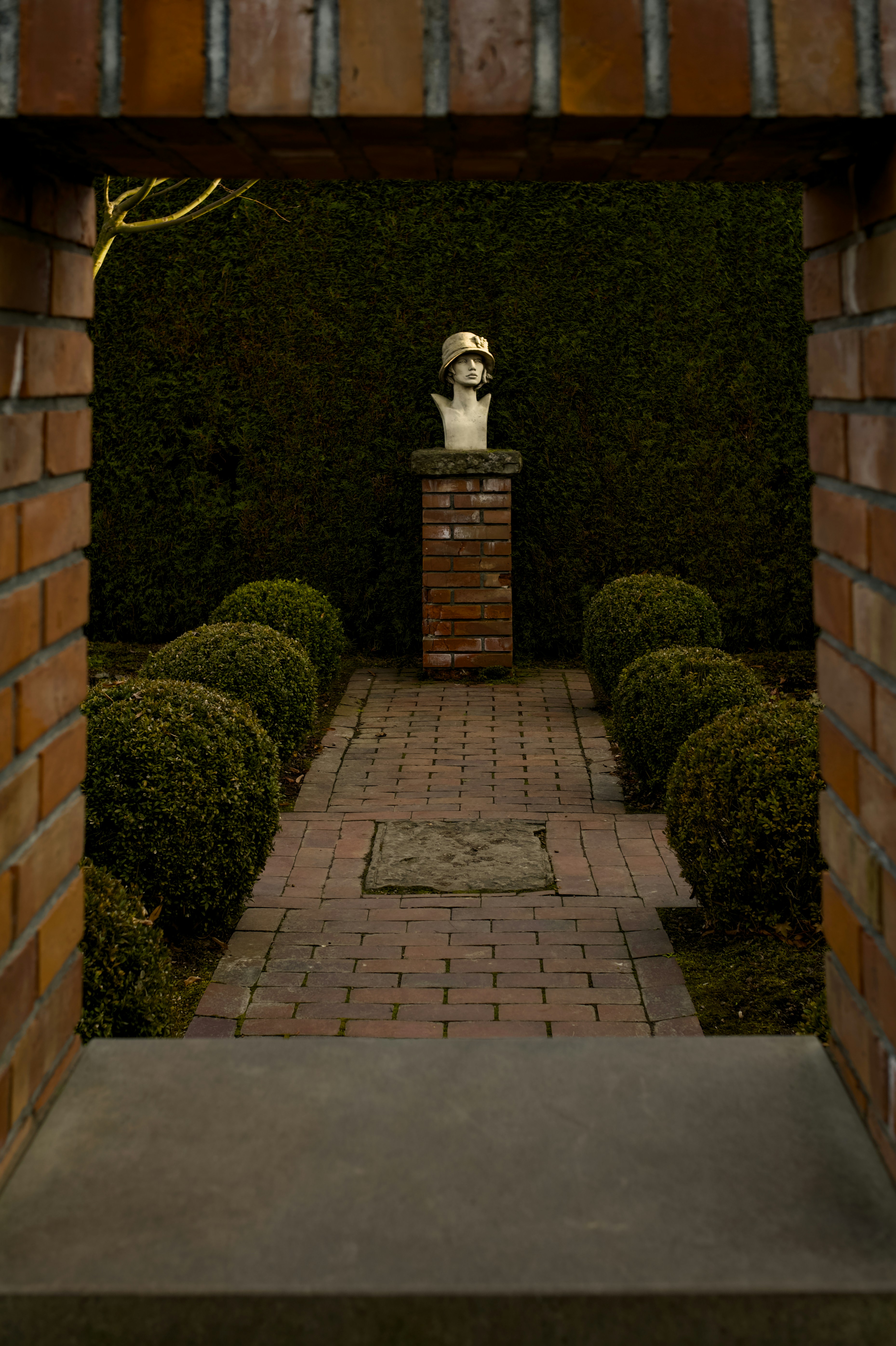 Stone Statue in a Brick-Framed Garden Corridor