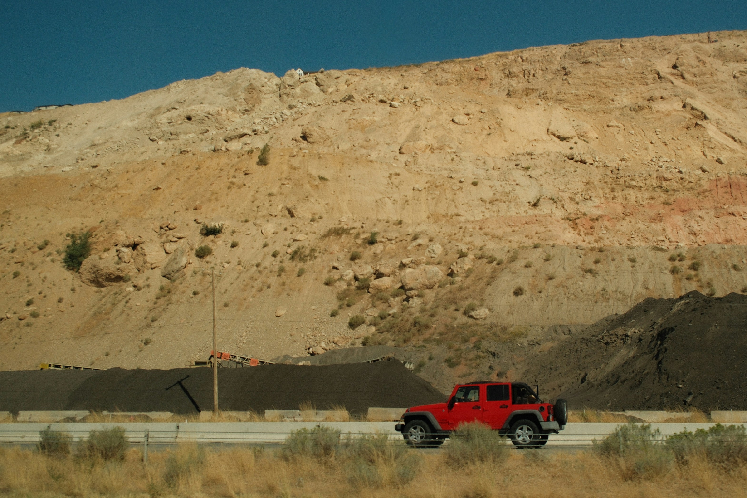 Red Jeep against a layered desert hillside